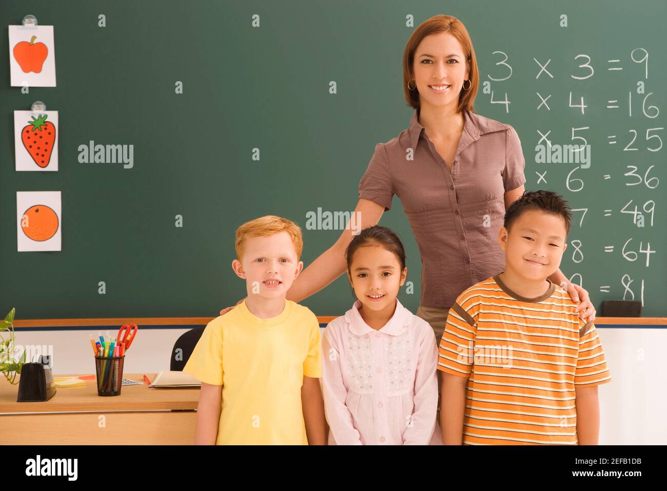 Portrait of a female teacher standing with her three students in a ...