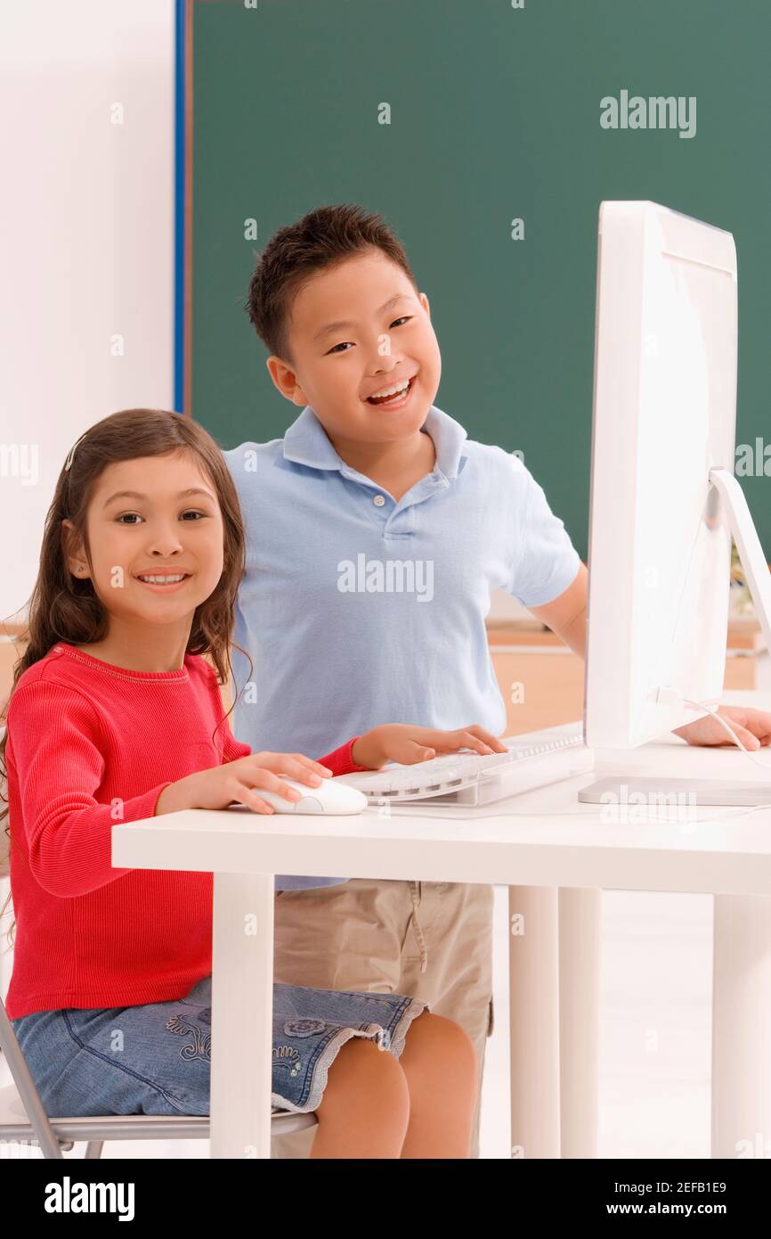 Portrait of a schoolboy and a schoolgirl using a computer in a ...