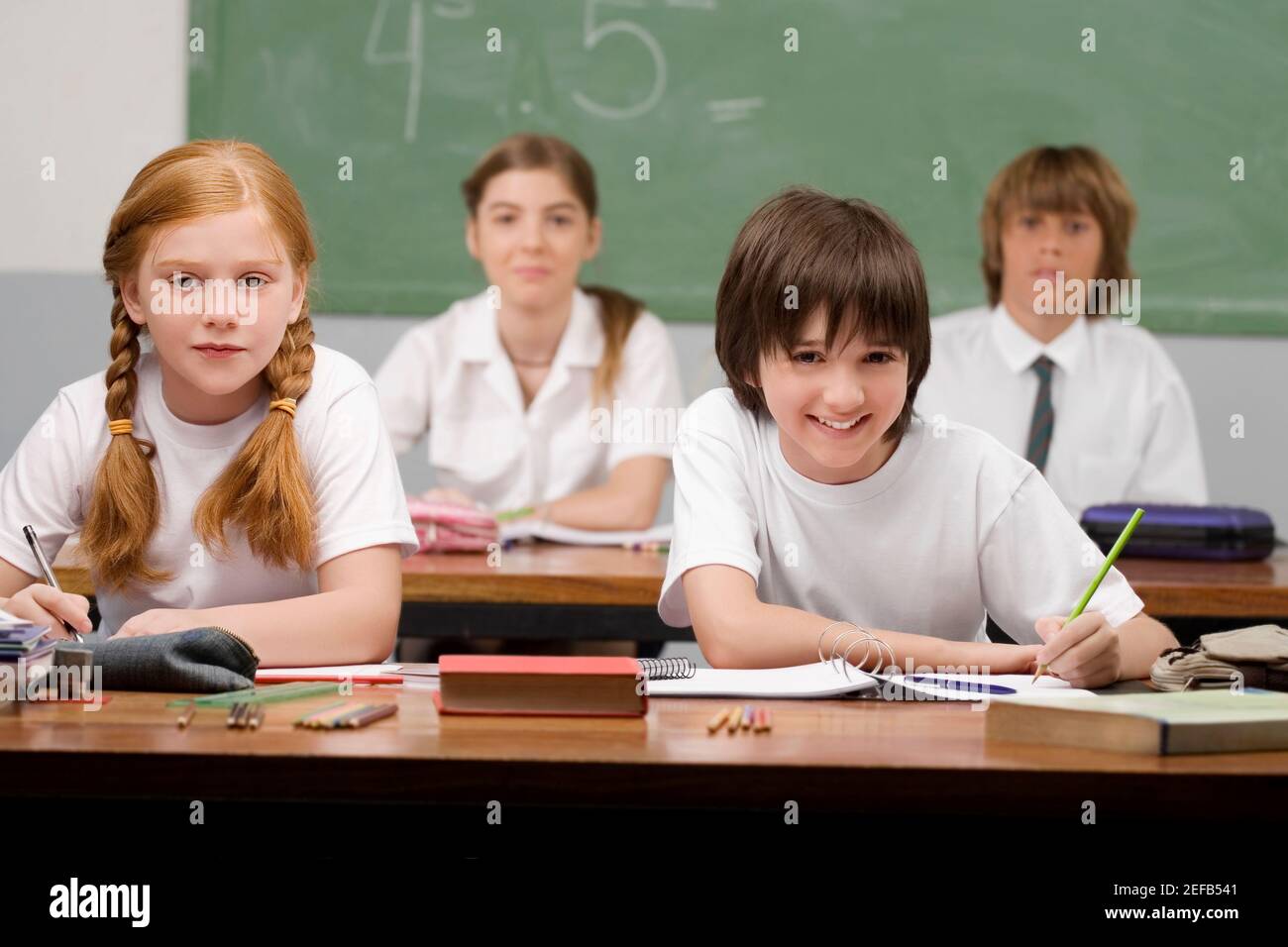 Portrait of four school students sitting in a classroom Stock Photo - Alamy