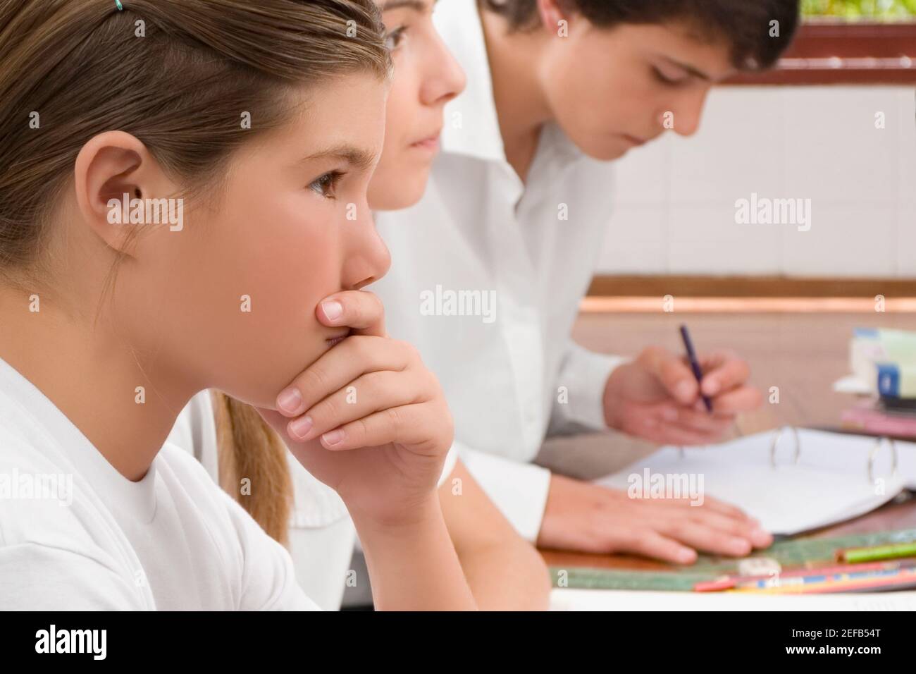 Two schoolgirls with a schoolboy studying in a classroom Stock Photo ...
