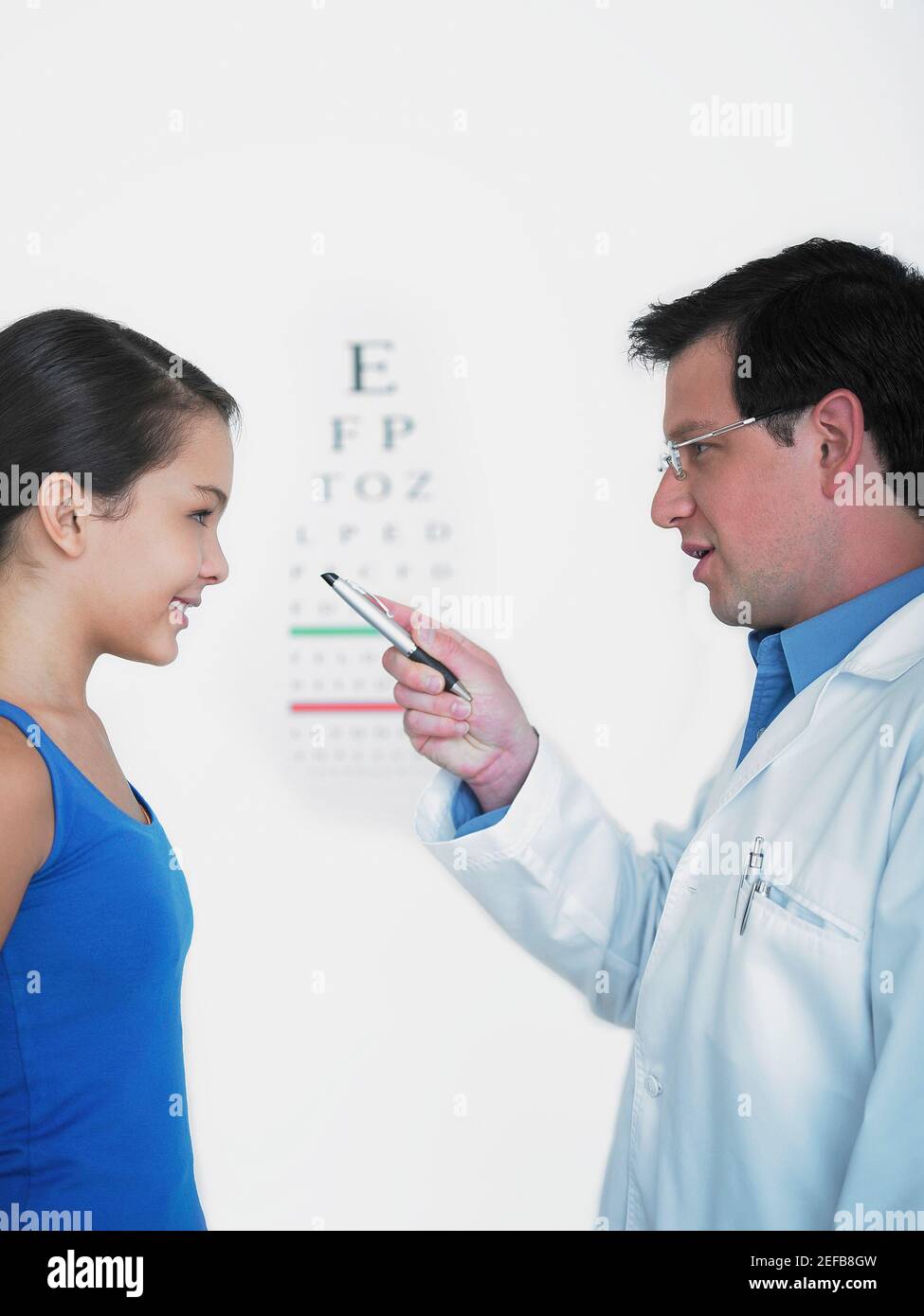 Side profile of a male doctor doing an eye exam of a female patient ...