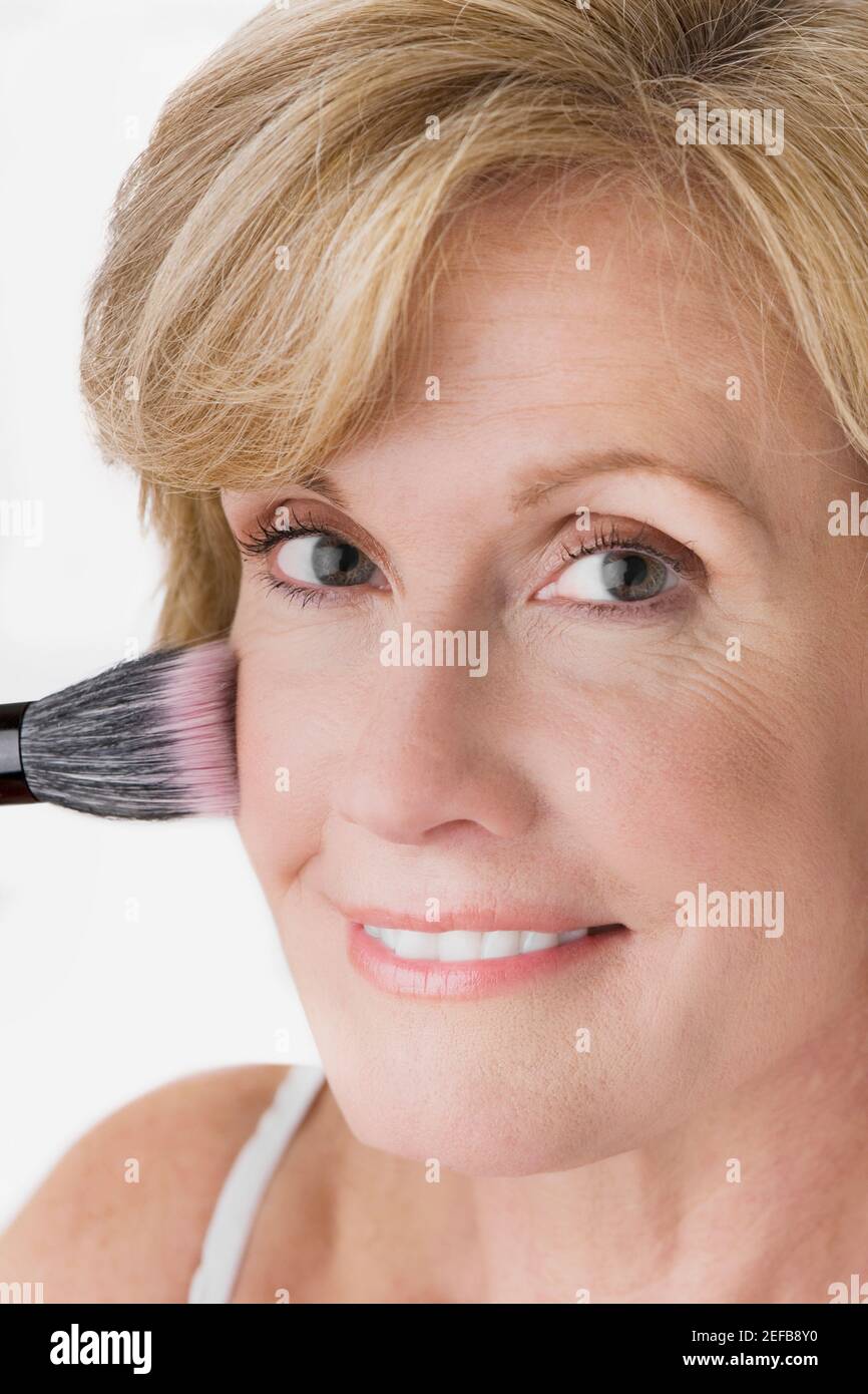 Portrait of a mature woman applying blush on her face Stock Photo - Alamy