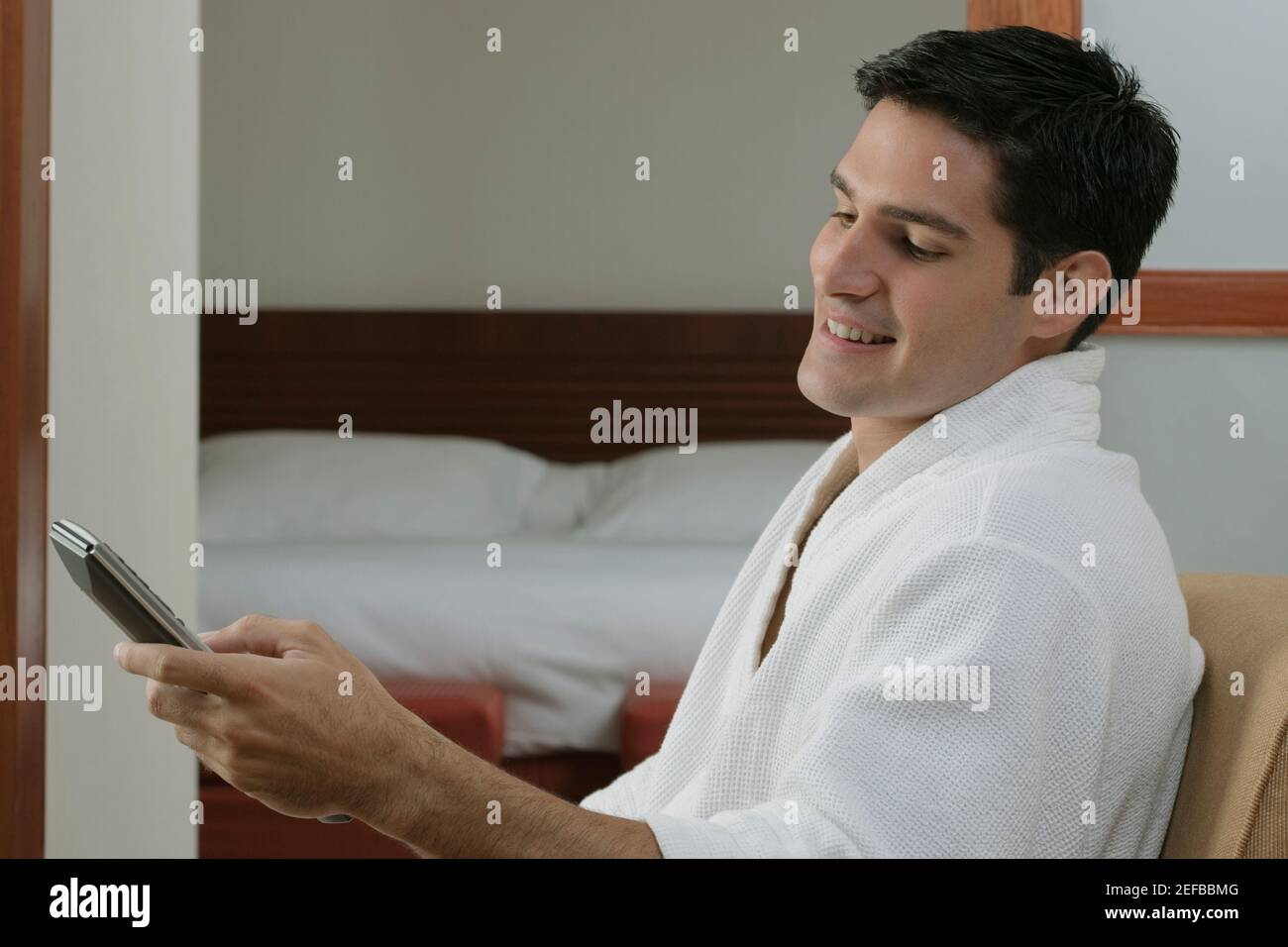 Side profile of a young man holding a remote control and smiling Stock ...