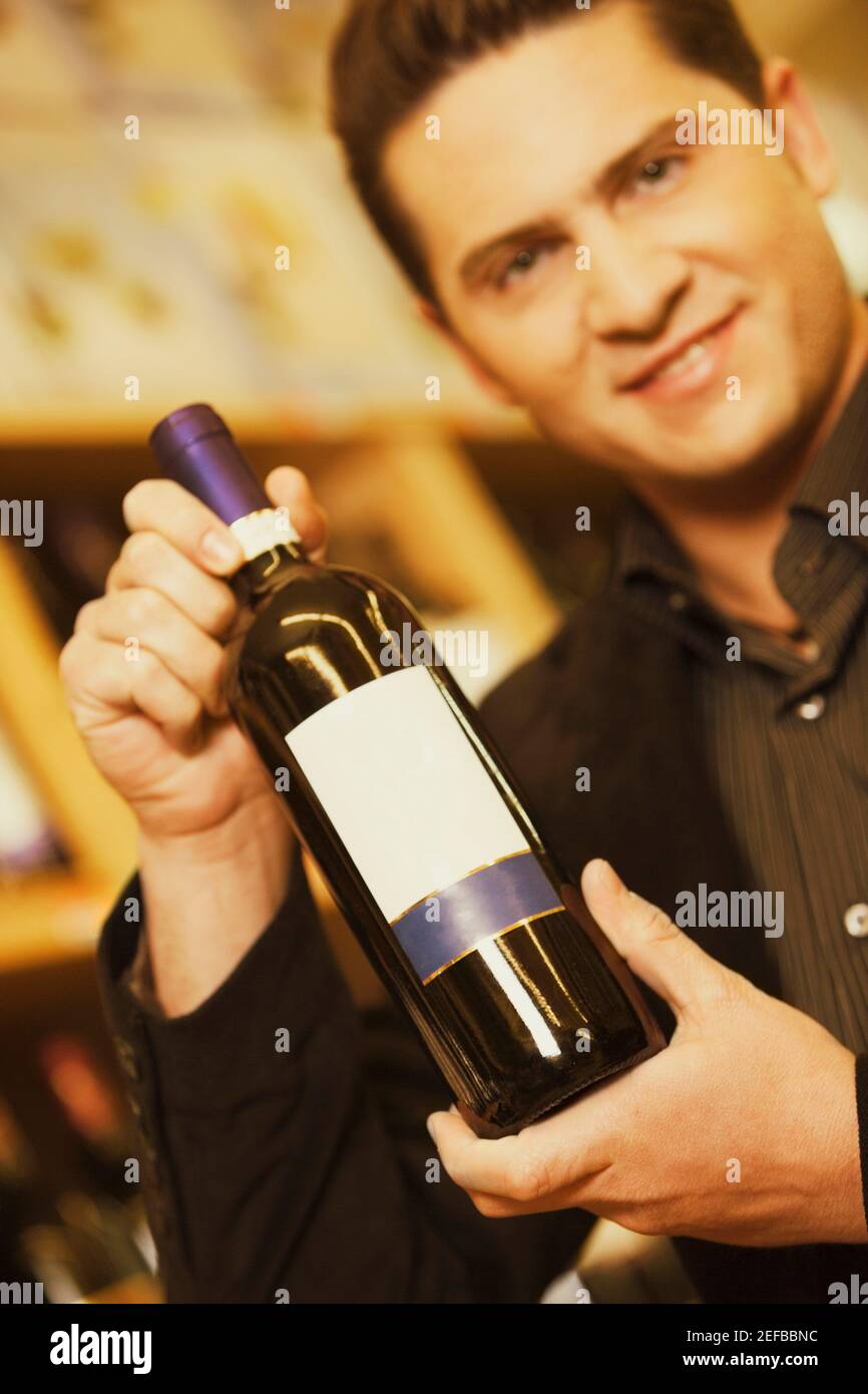 Portrait of a young man showing a wine bottle in a liquor store Stock ...