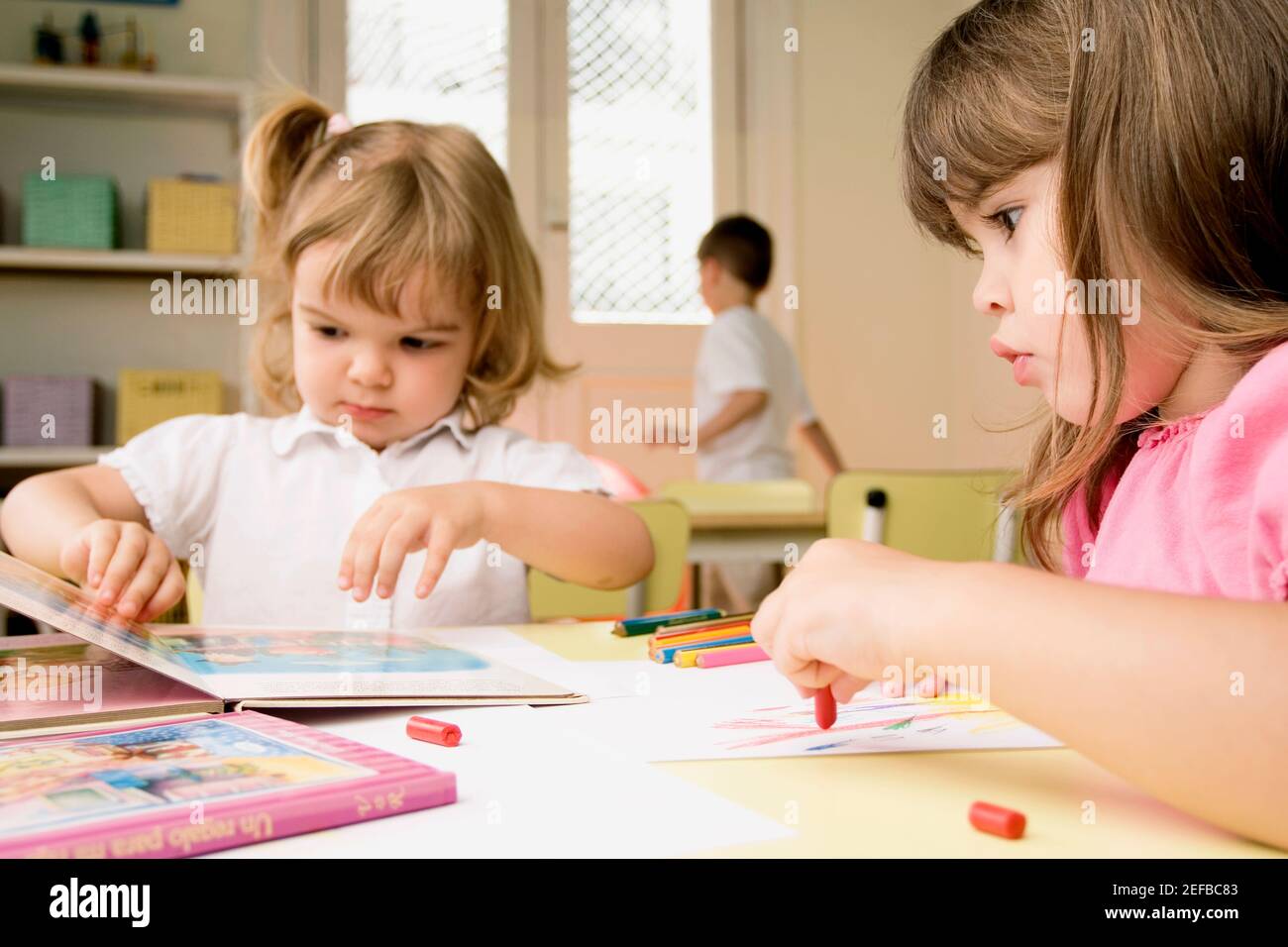 Two girls drawing on sheets of paper Stock Photo - Alamy