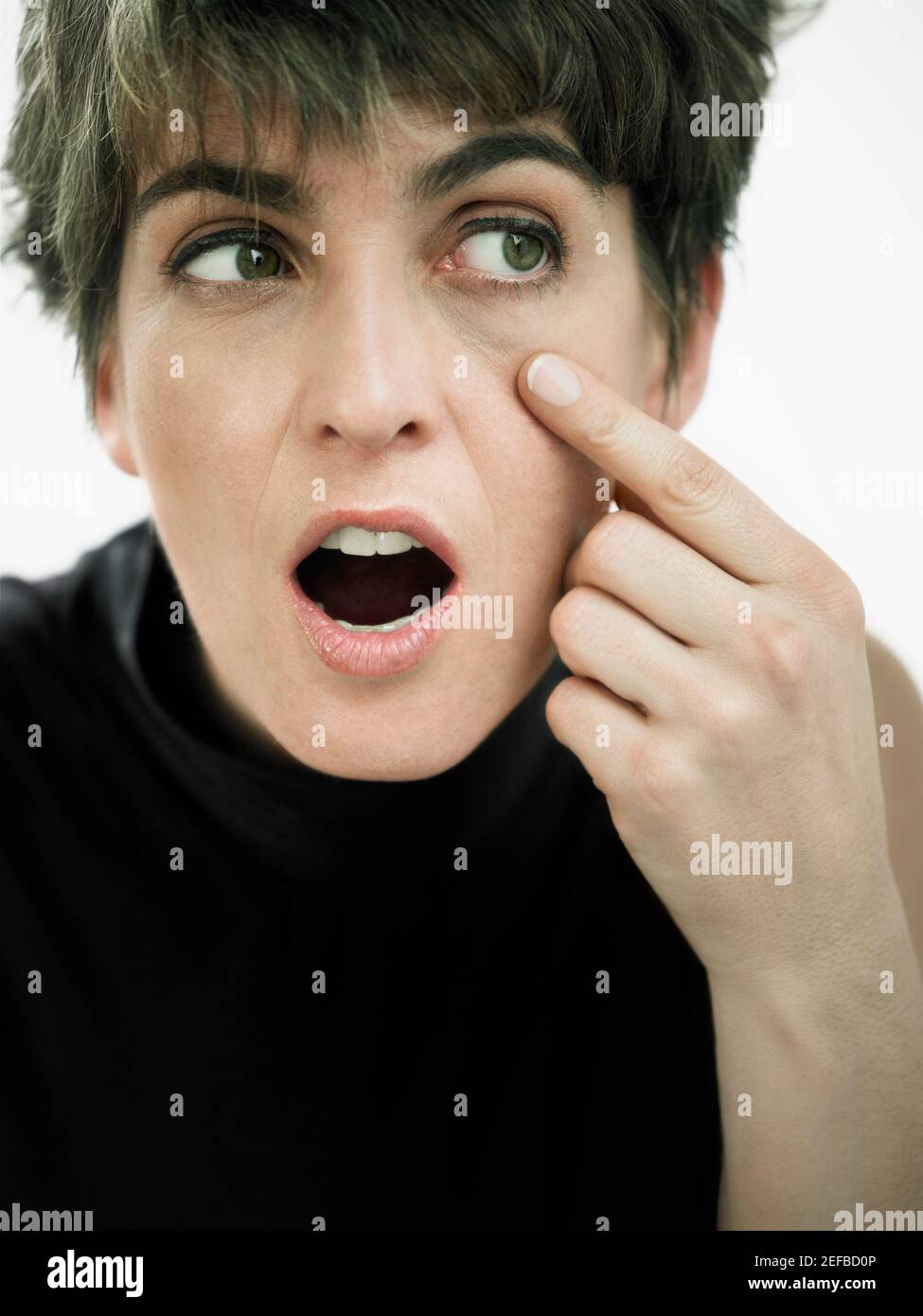 Close-up of a mature woman pointing towards her eye Stock Photo - Alamy