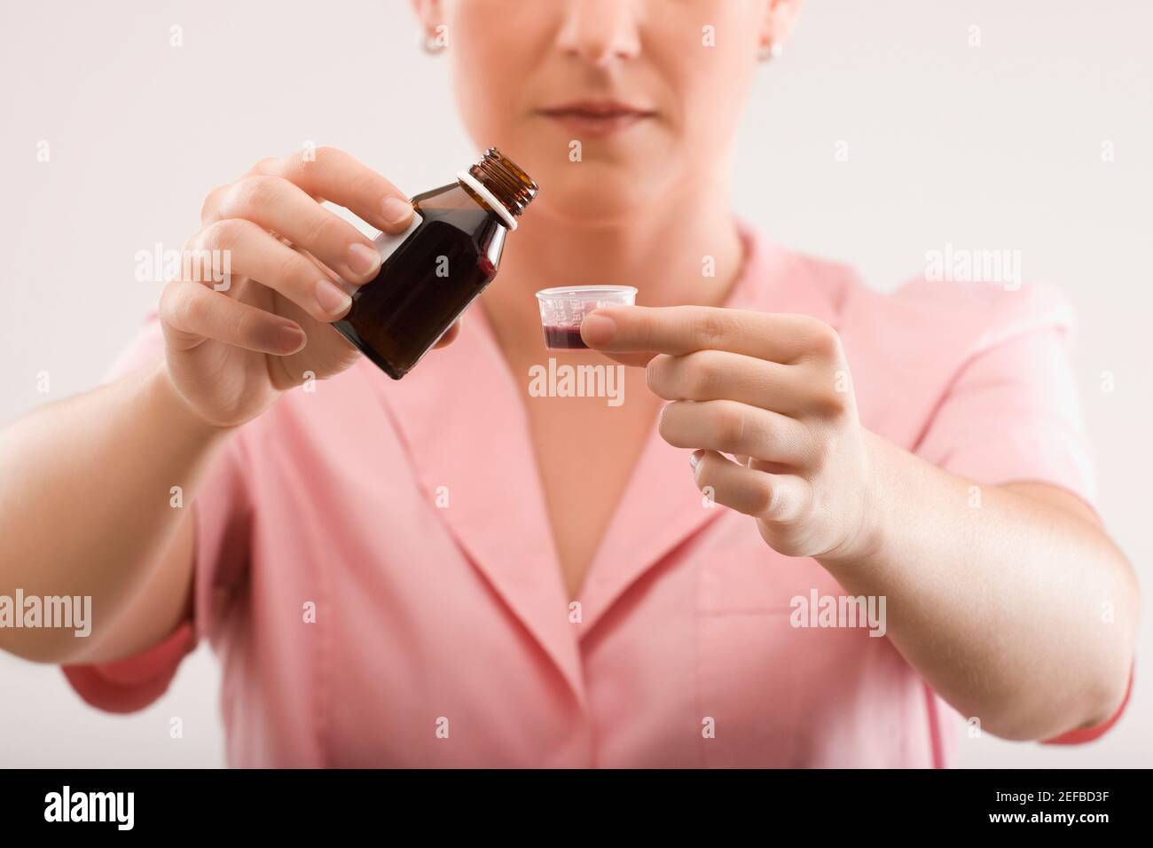 Female nurse pouring syrup into a bottle cap Stock Photo - Alamy