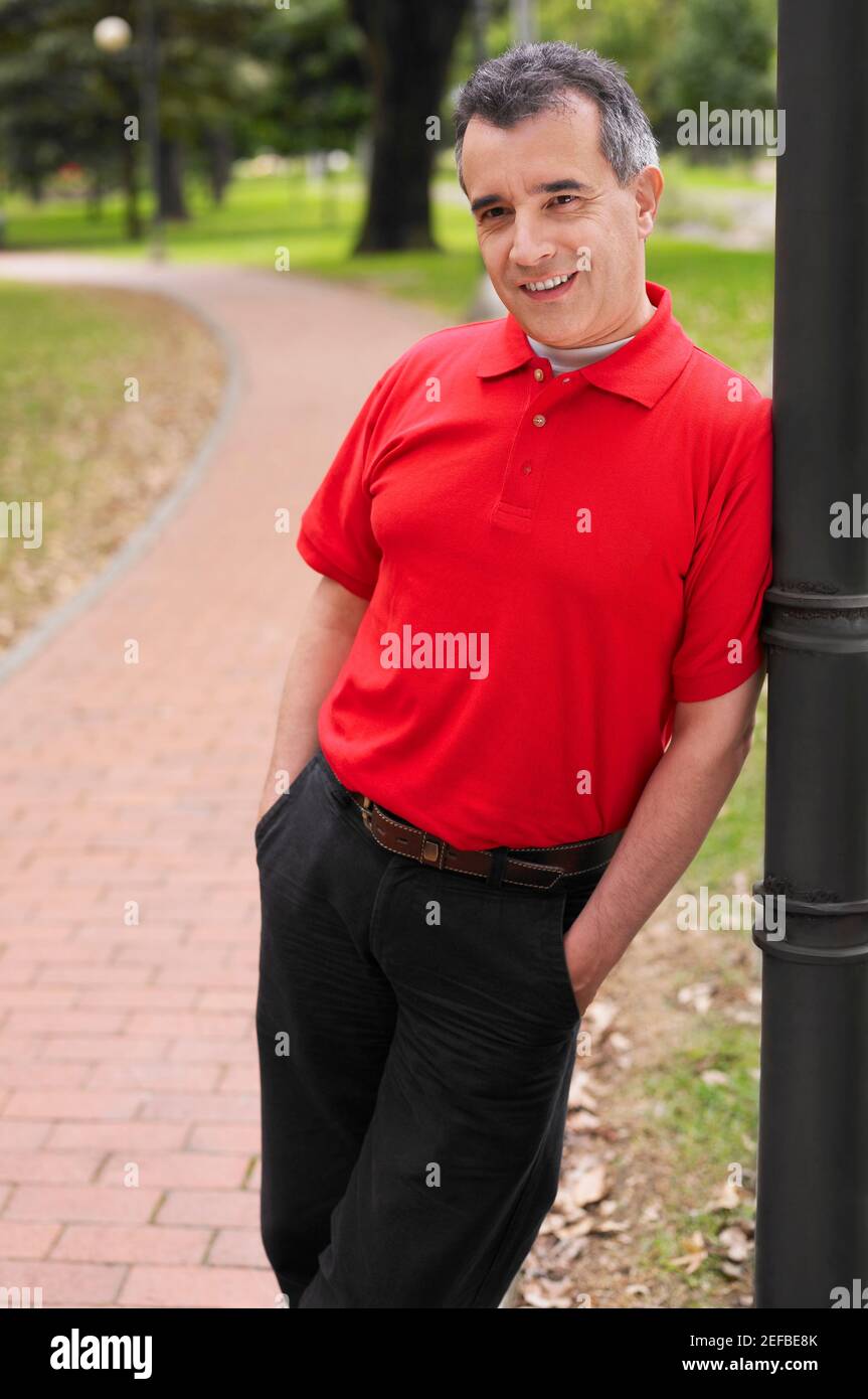 Portrait of a mid adult man leaning against a pole Stock Photo - Alamy
