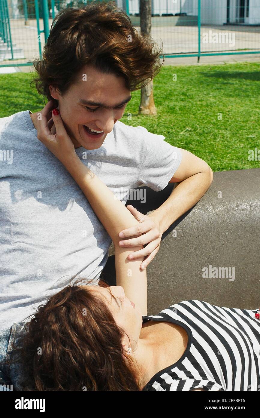 Young woman lying on a bench resting her head in the lap of a young man Stock Photo - Alamy