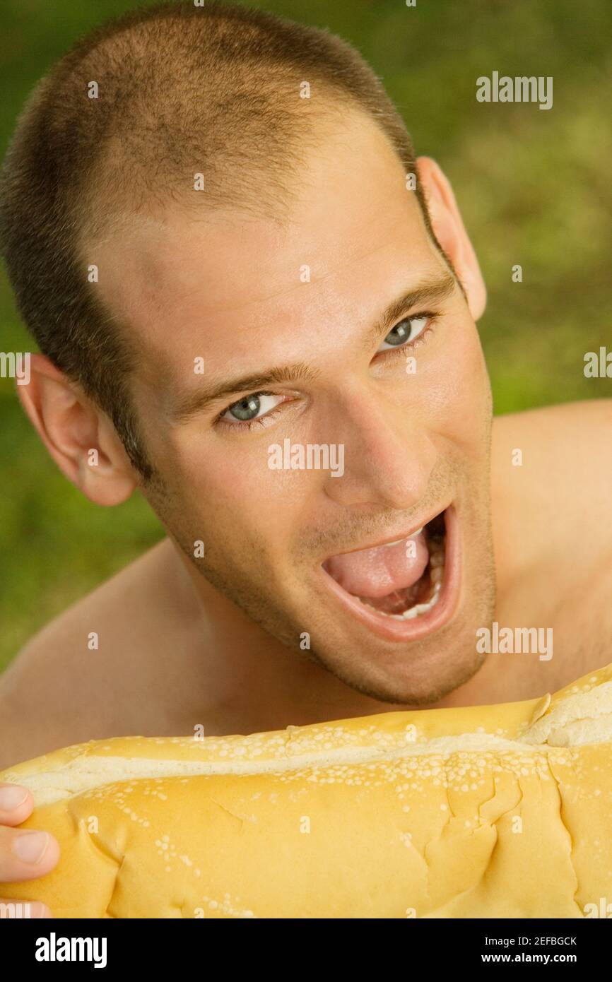 Portrait of a young man eating a loaf of baked bread Stock Photo - Alamy