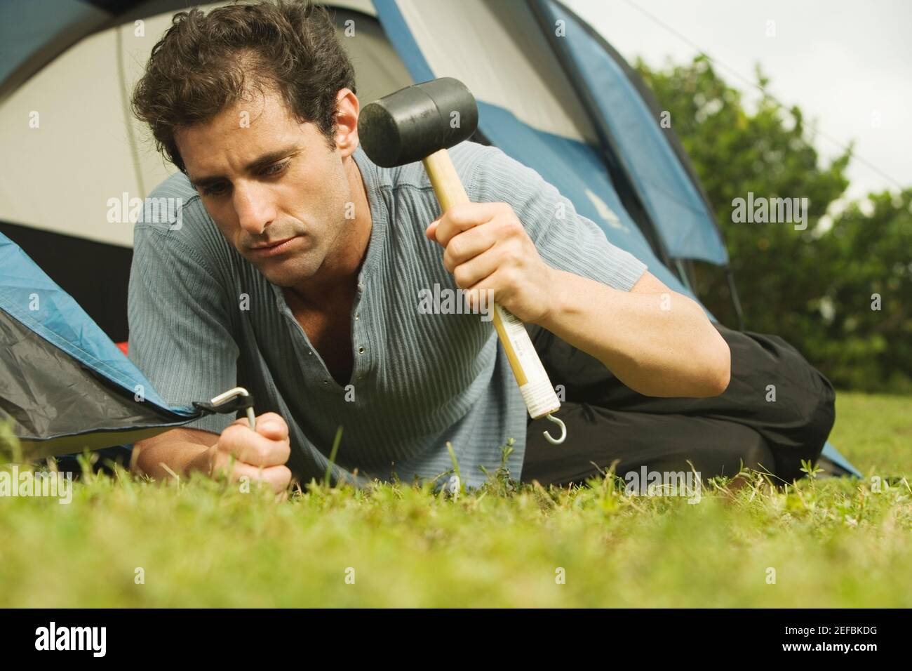 Close-up of a mid adult man putting up a tent Stock Photo - Alamy