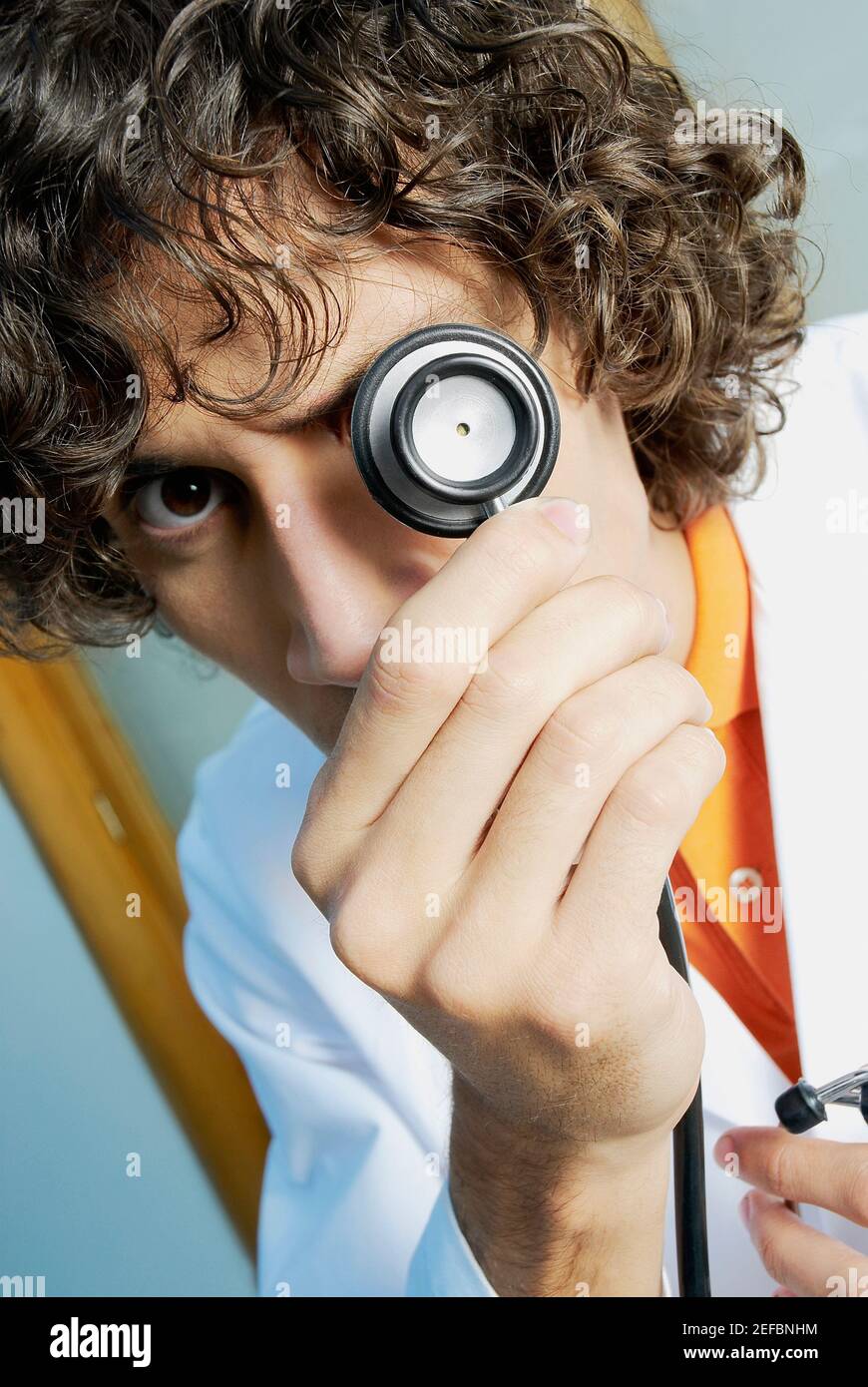 Portrait of a male doctor covering his eye with a stethoscope Stock ...