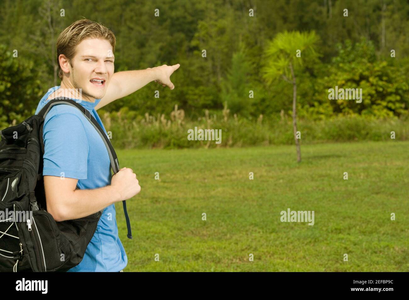 Portrait of a young man carrying a backpack pointing forward Stock ...
