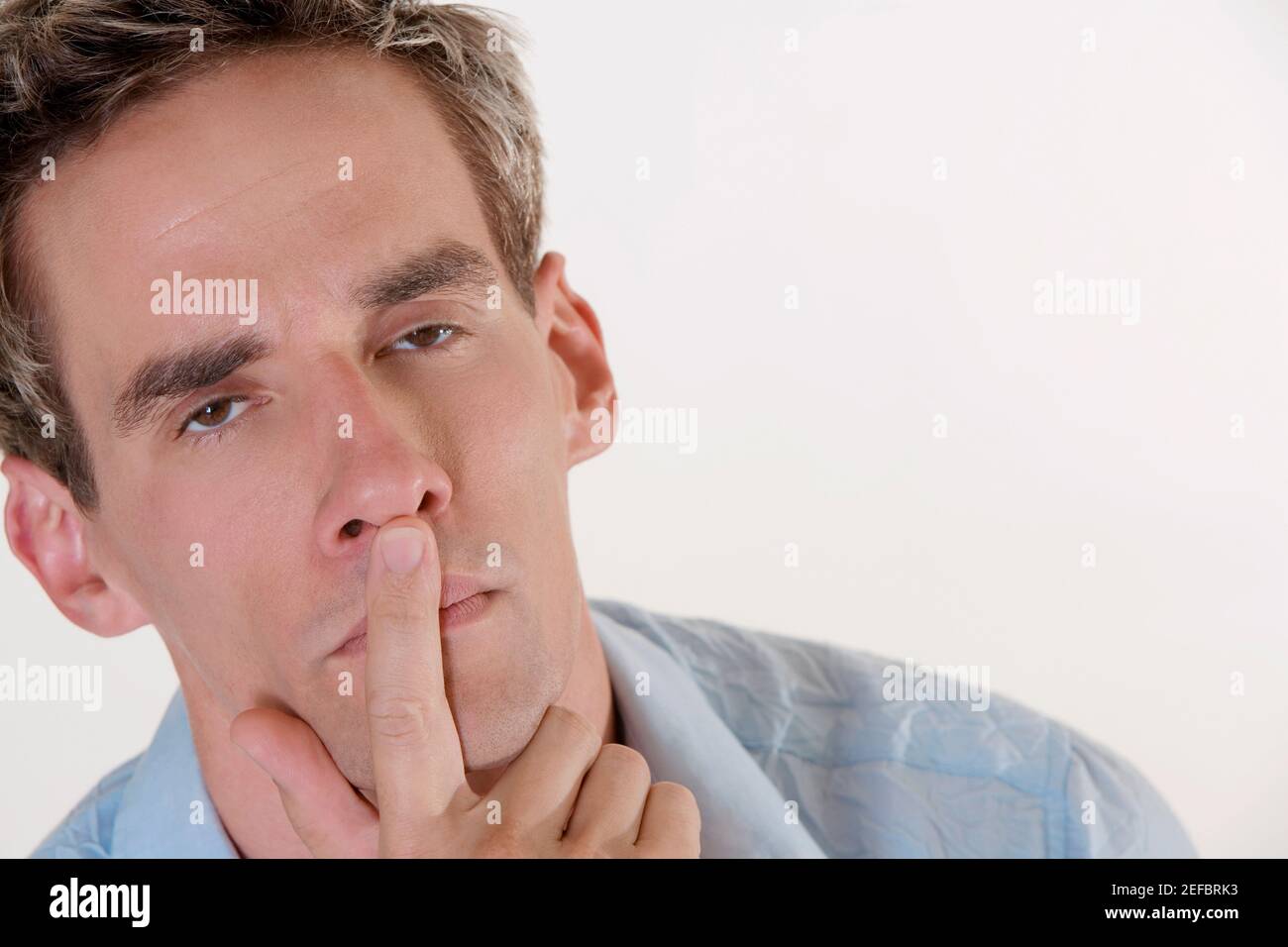 Portrait of a young man with his finger on his lips Stock Photo - Alamy
