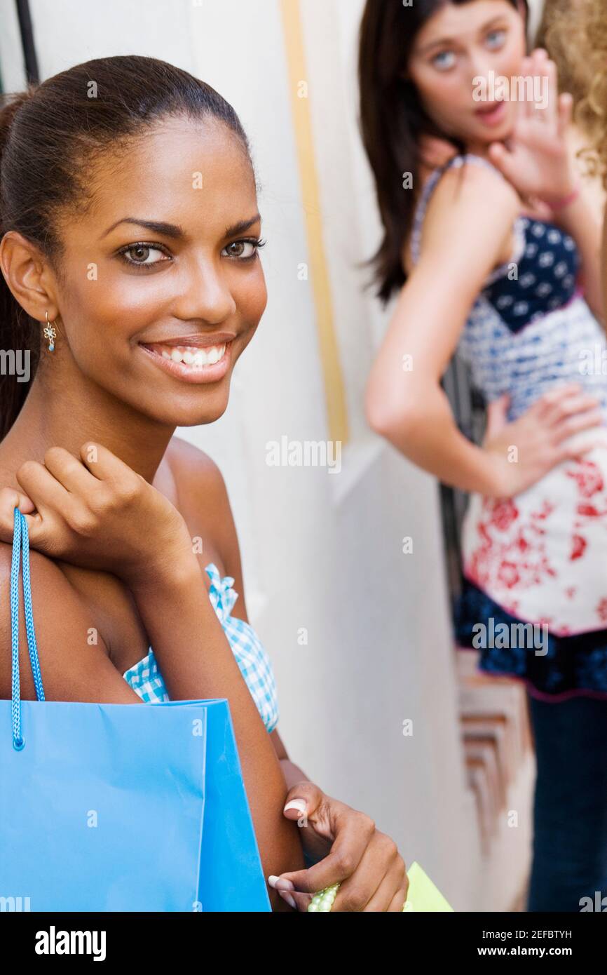 Portrait of a teenage girl smiling with another teenage girl standing ...