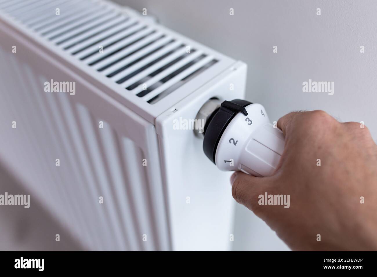 Woman holding temperature knob of heating radiator Stock Photo - Alamy