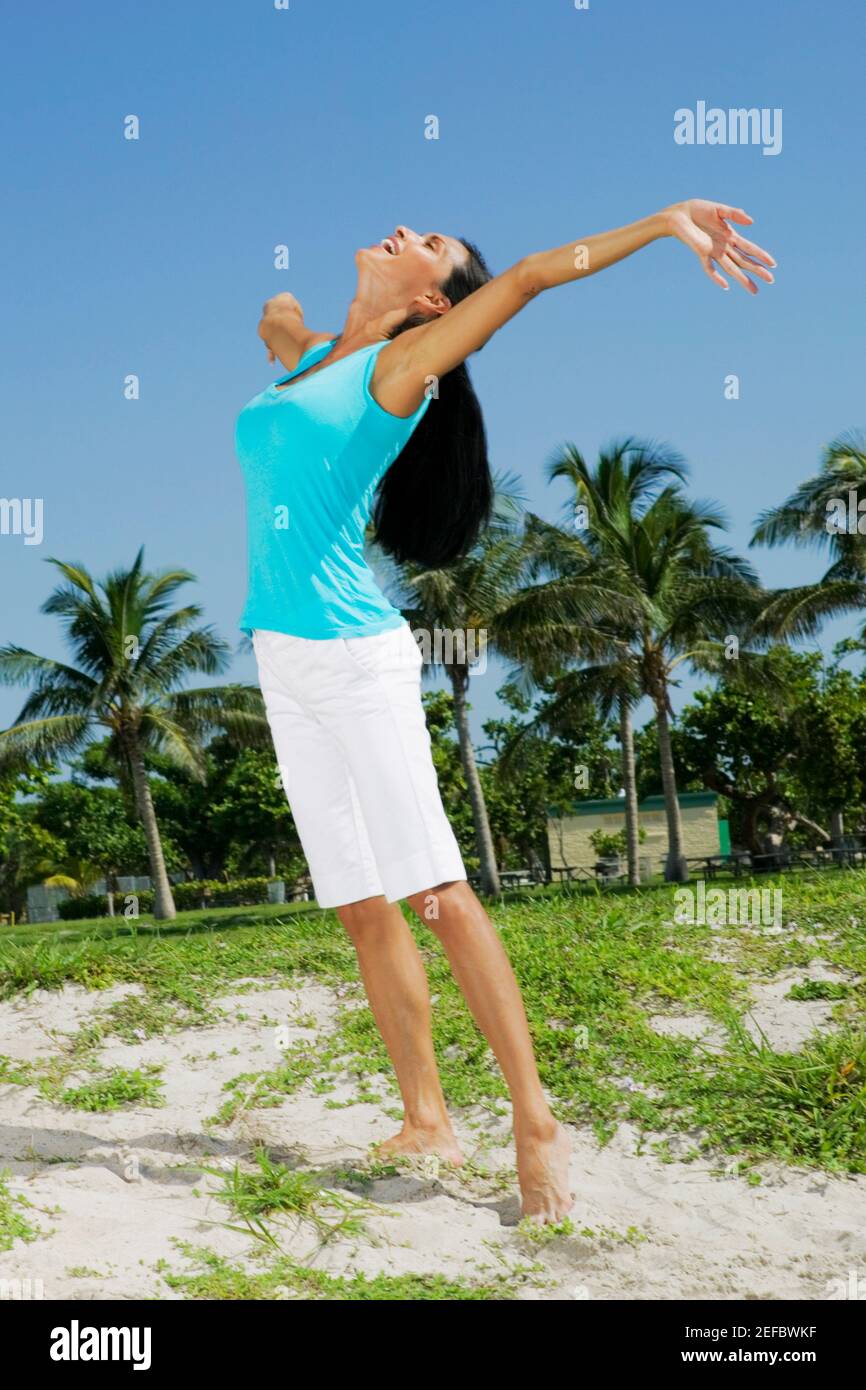 Side profile of a young woman standing with her arms outstretched Stock ...