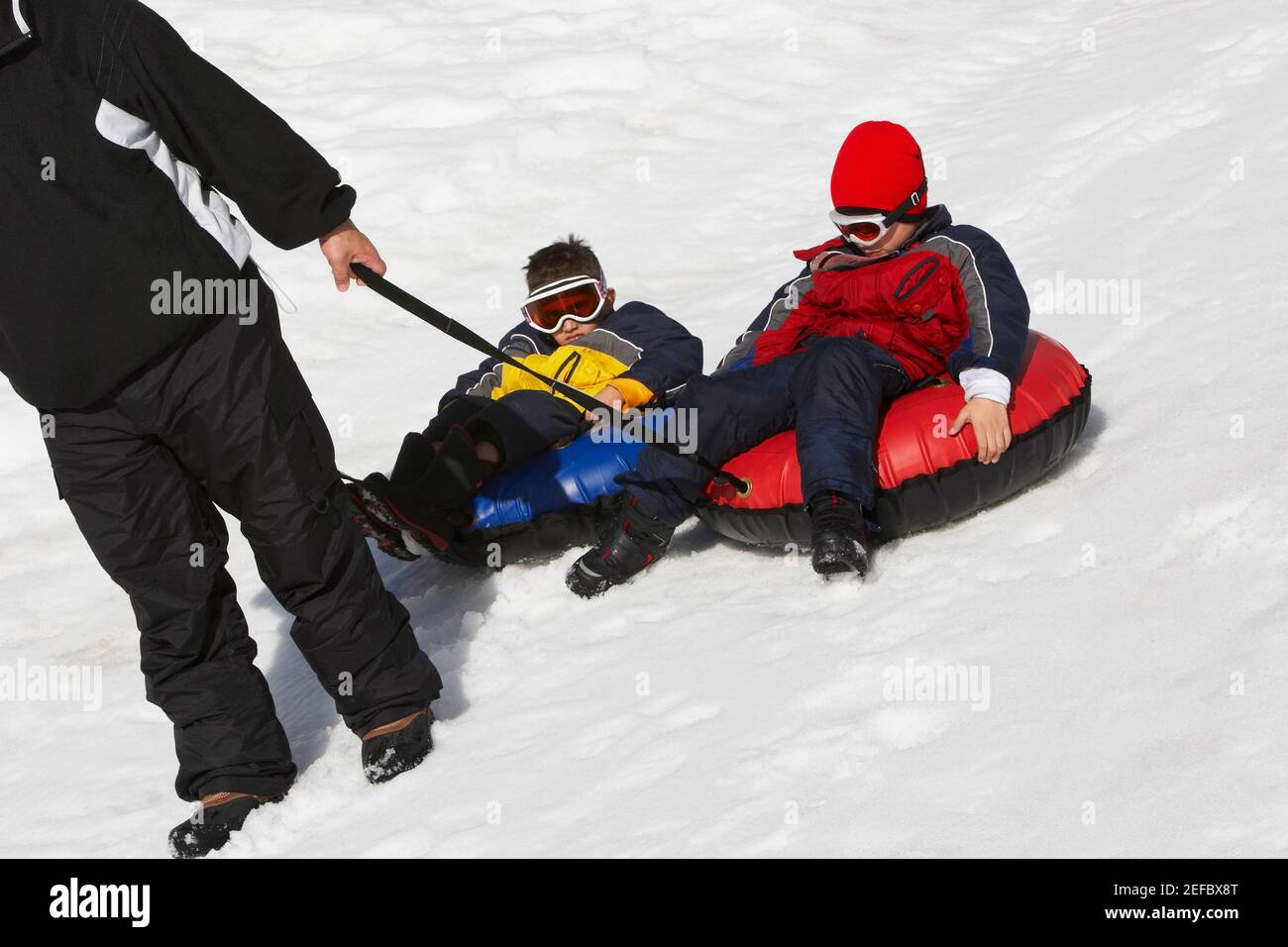 Low section view of a person pulling an inner tube with his children ...