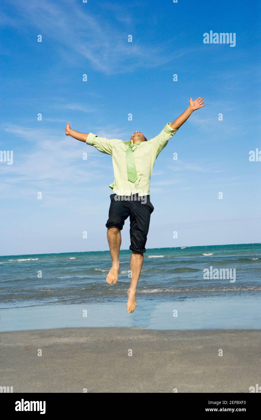 Man beach arms up jumping hi-res stock photography and images - Alamy