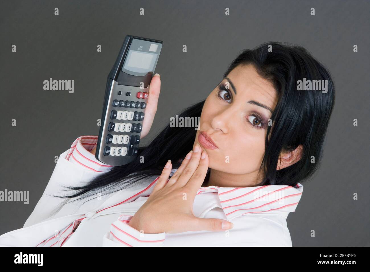 Portrait of a businesswoman holding a calculator and making a face ...
