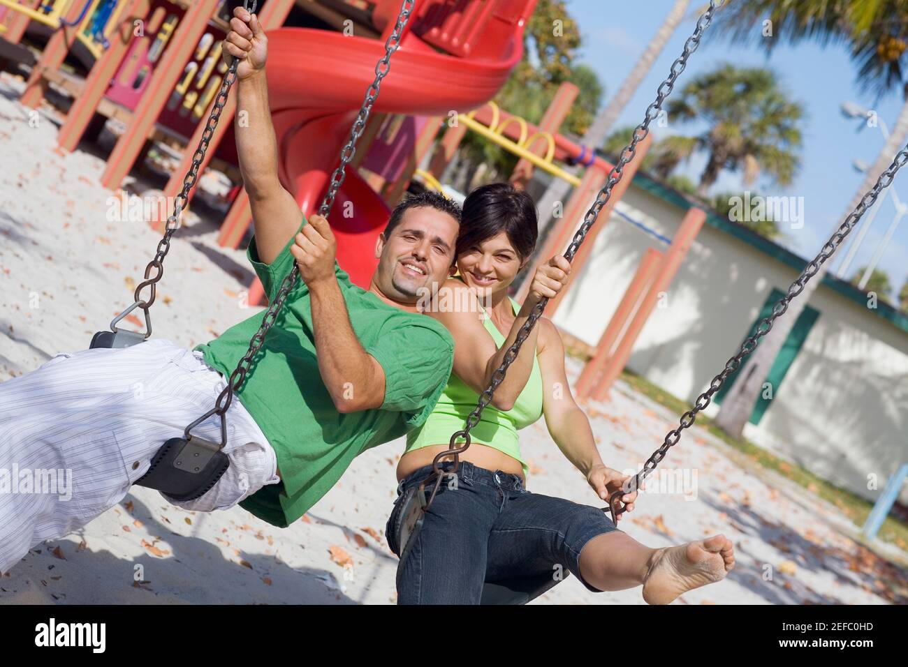Portrait of a mid adult woman swinging on a swing with her husband ...
