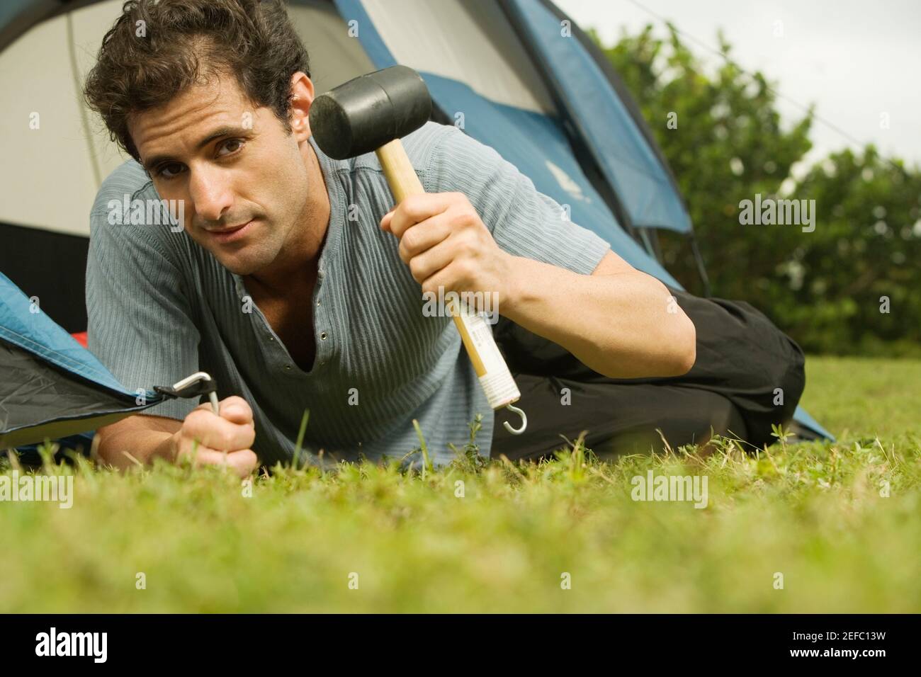 Portrait of a mid adult man putting up a tent Stock Photo - Alamy