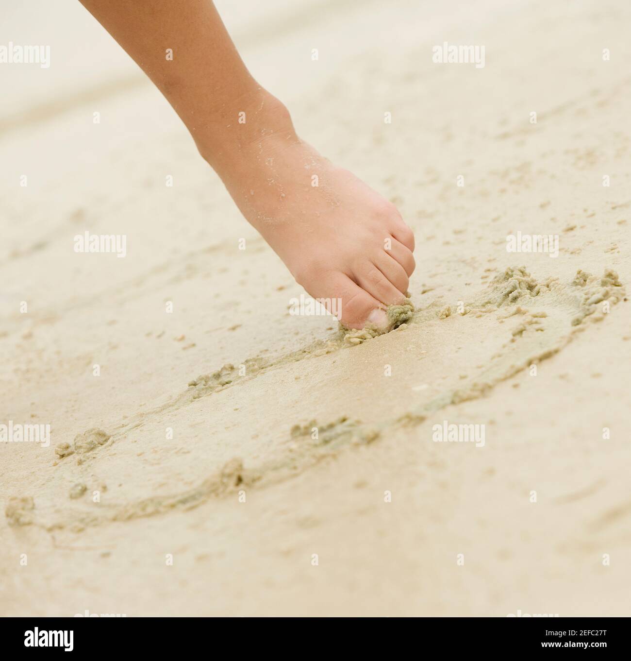 Low section view of a woman drawing in sand with her toe Stock Photo ...