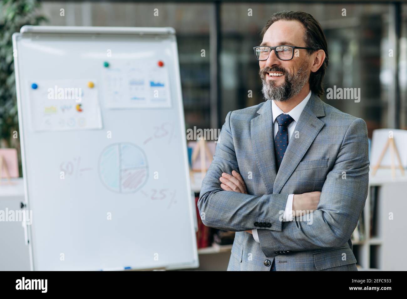 Influential serious ceo stands near marker board at the workplace ...