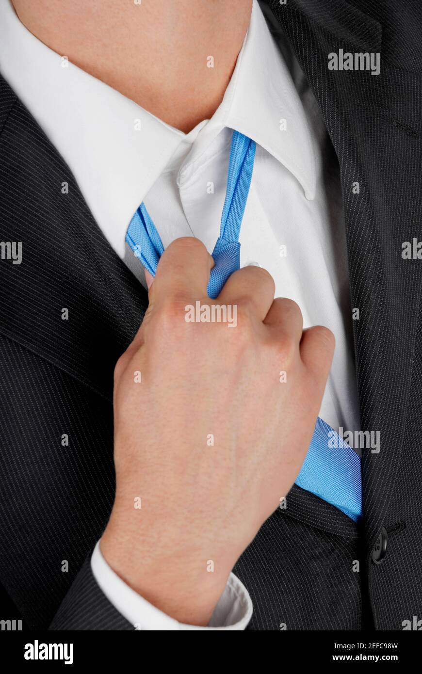 Mid section view of a businessman pulling his tie Stock Photo - Alamy