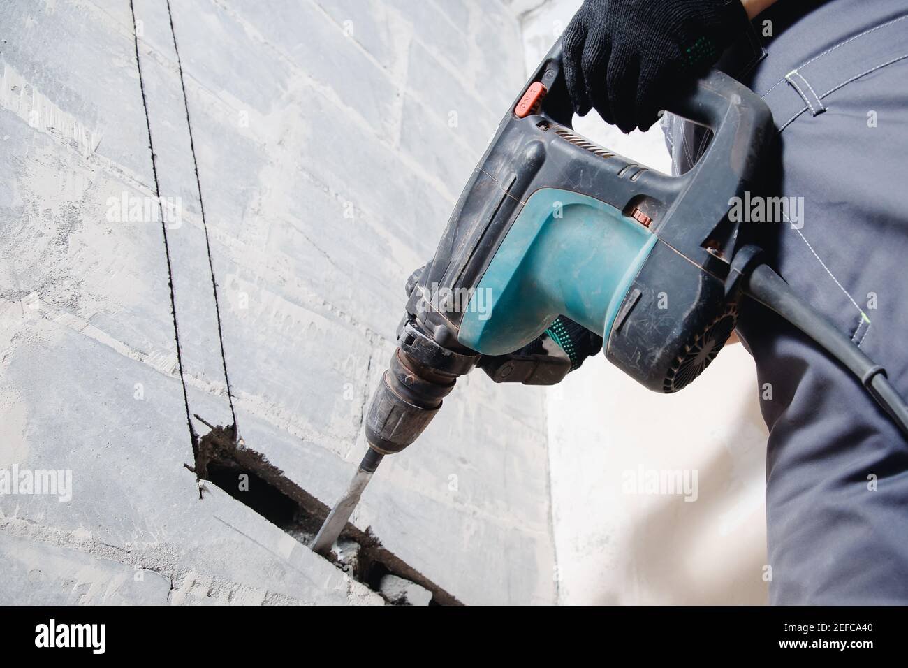 Builder worker man using jackhammer to drill into construction wall for ...
