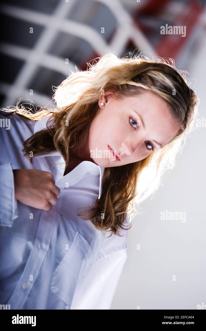 Close-up of a young woman buttoning her shirt Stock Photo - Alamy