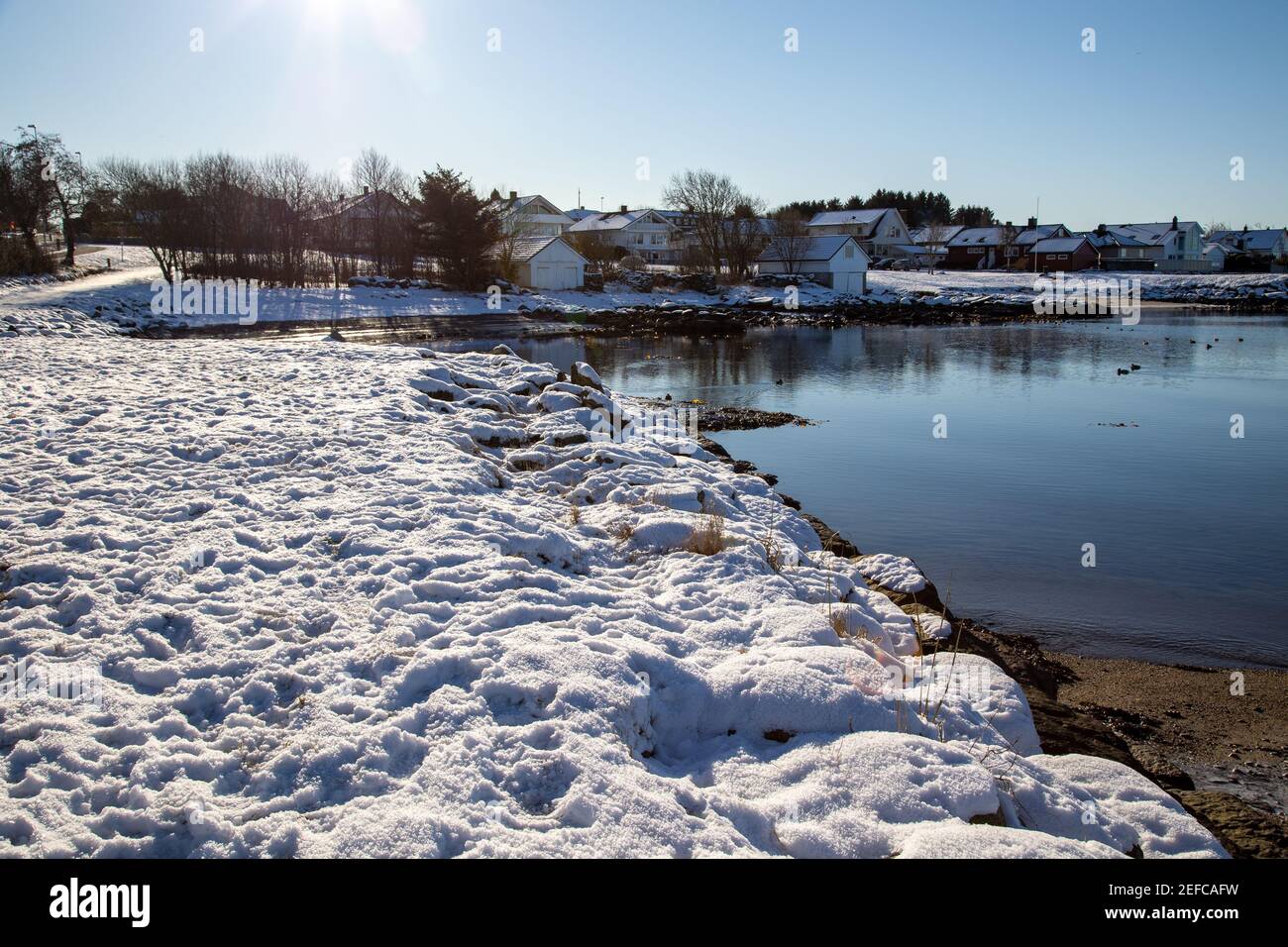 Chilling view of a calm lake near a village under a clear blue sky ...