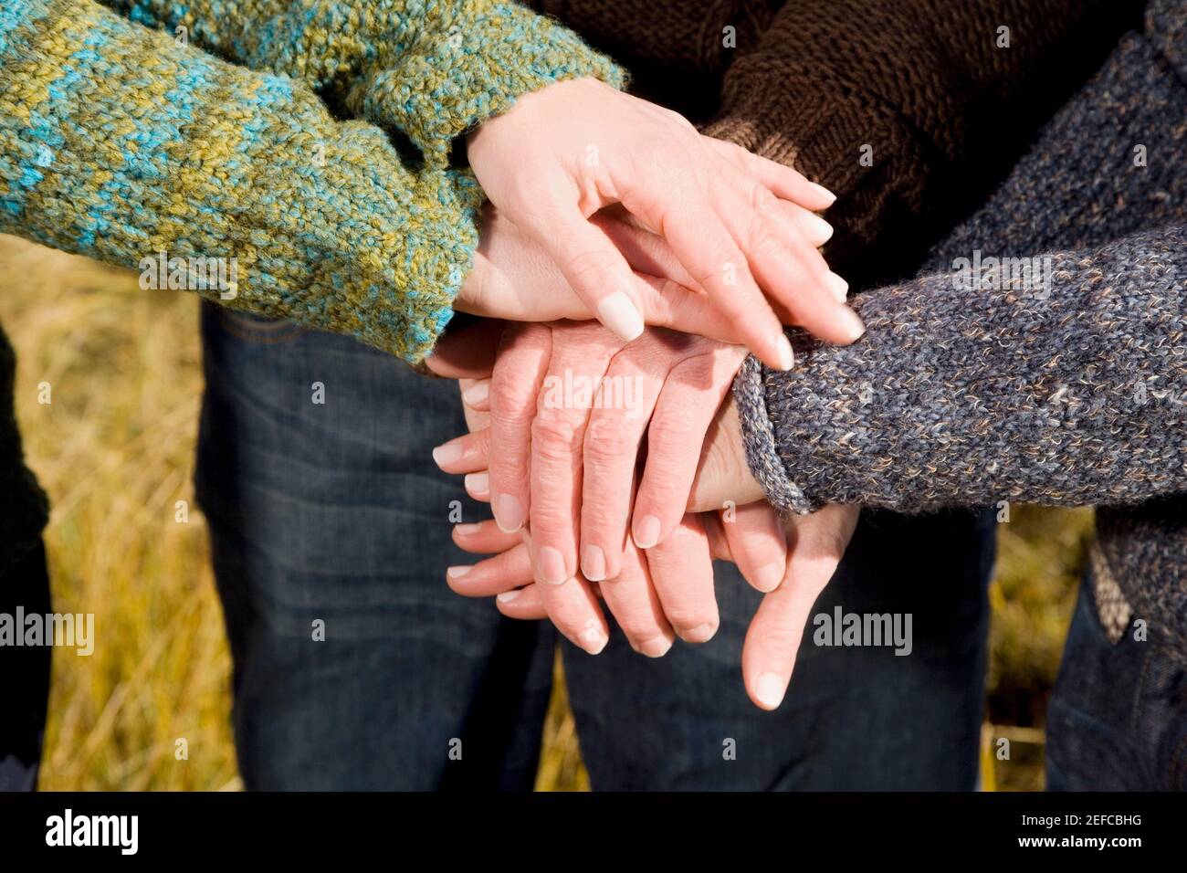 Three people stacking hands Stock Photo - Alamy