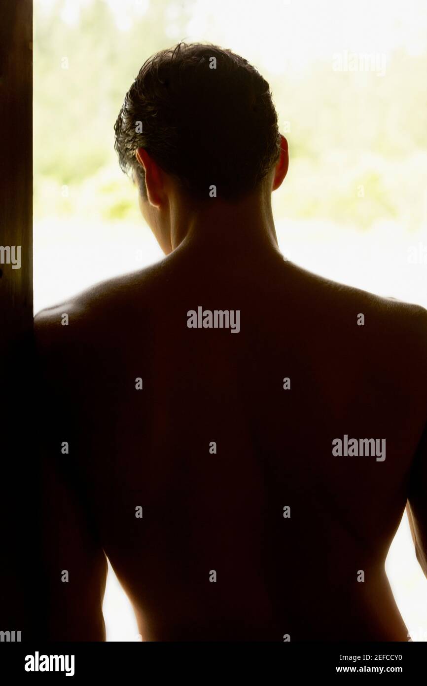 Rear view of a mid adult man leaning against a door Stock Photo - Alamy