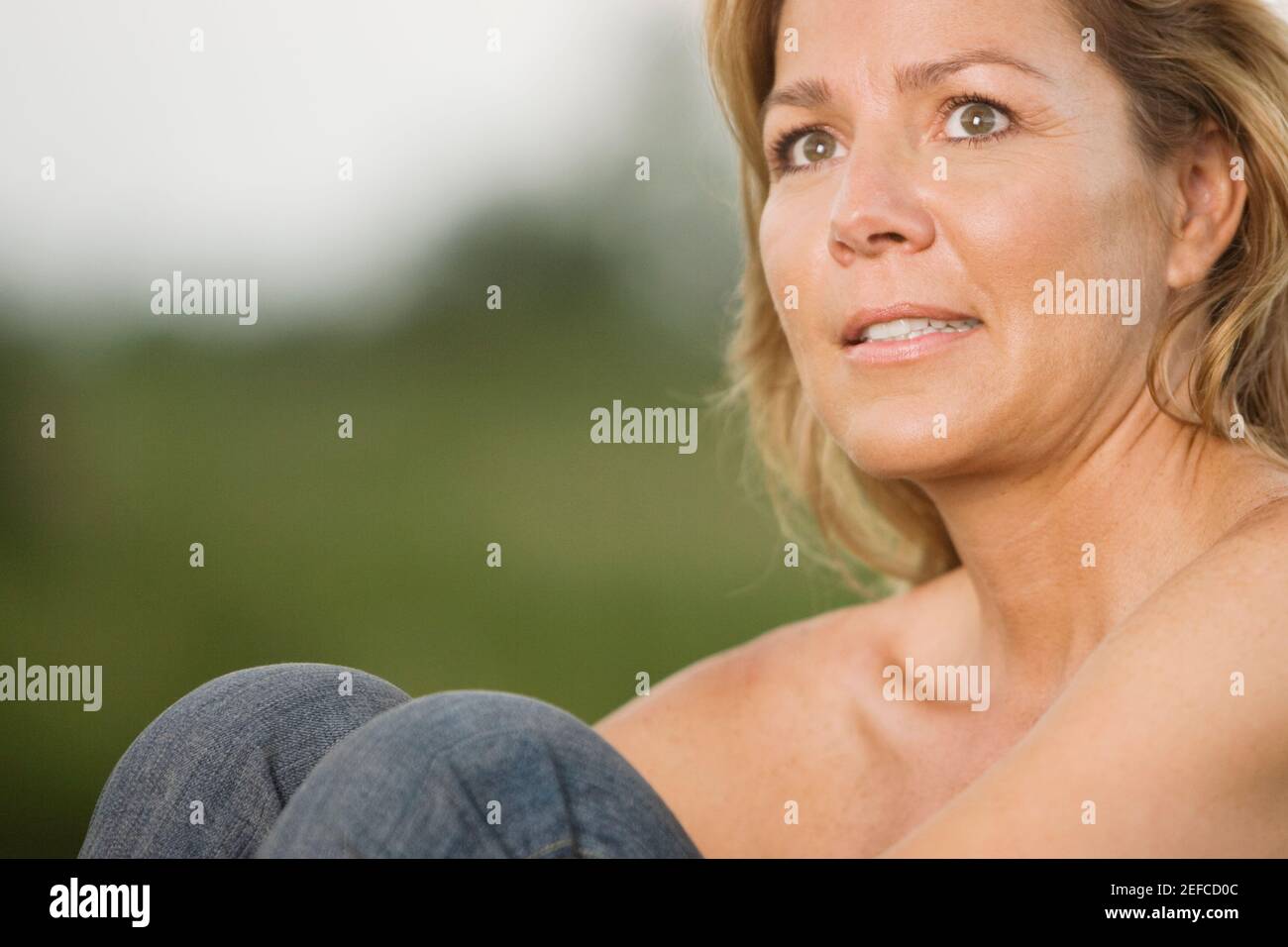 Side profile of a mature woman hugging her knees Stock Photo - Alamy