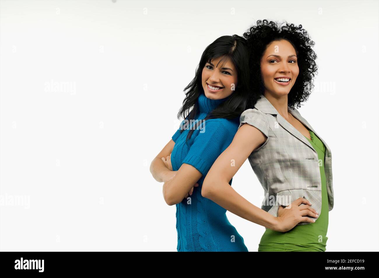 Side profile of two young women standing back to back and smiling Stock ...