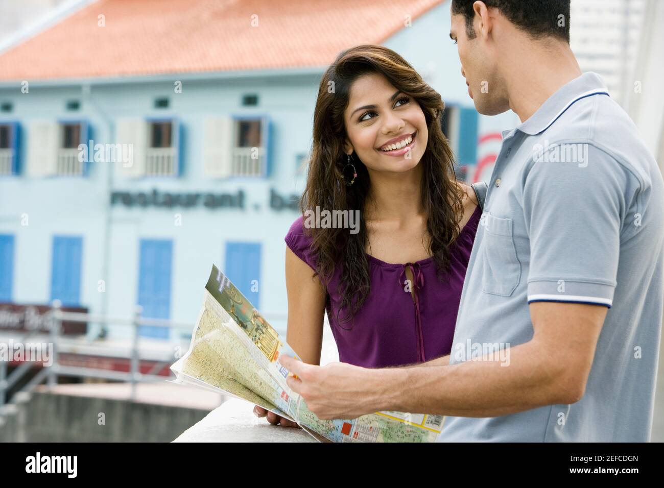 Couple holding a map and smiling Stock Photo - Alamy