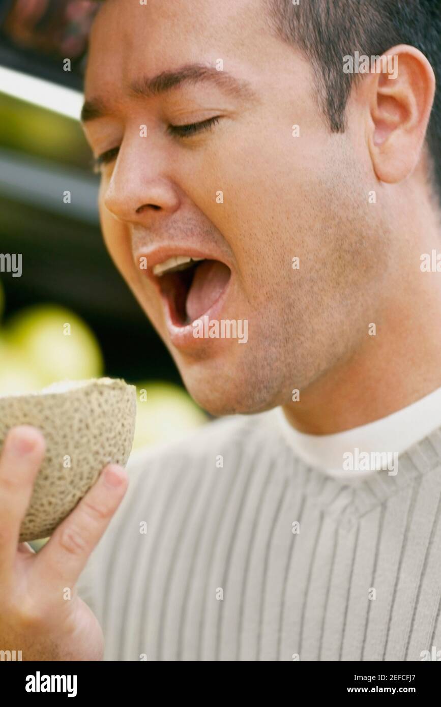 Close up of a mid adult man eating a cantaloupe Stock Photo - Alamy