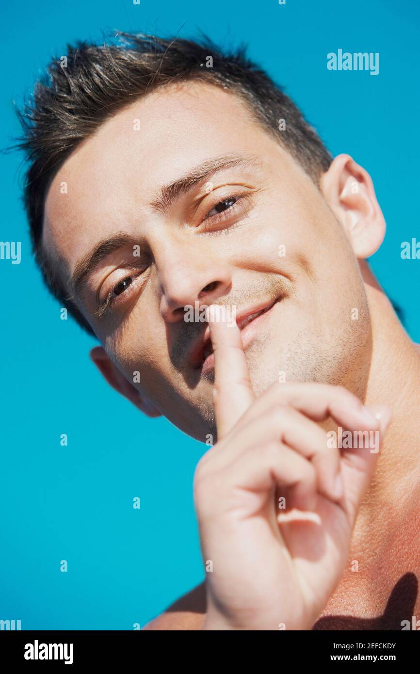 Portrait of a young man with his finger on his lips Stock Photo - Alamy