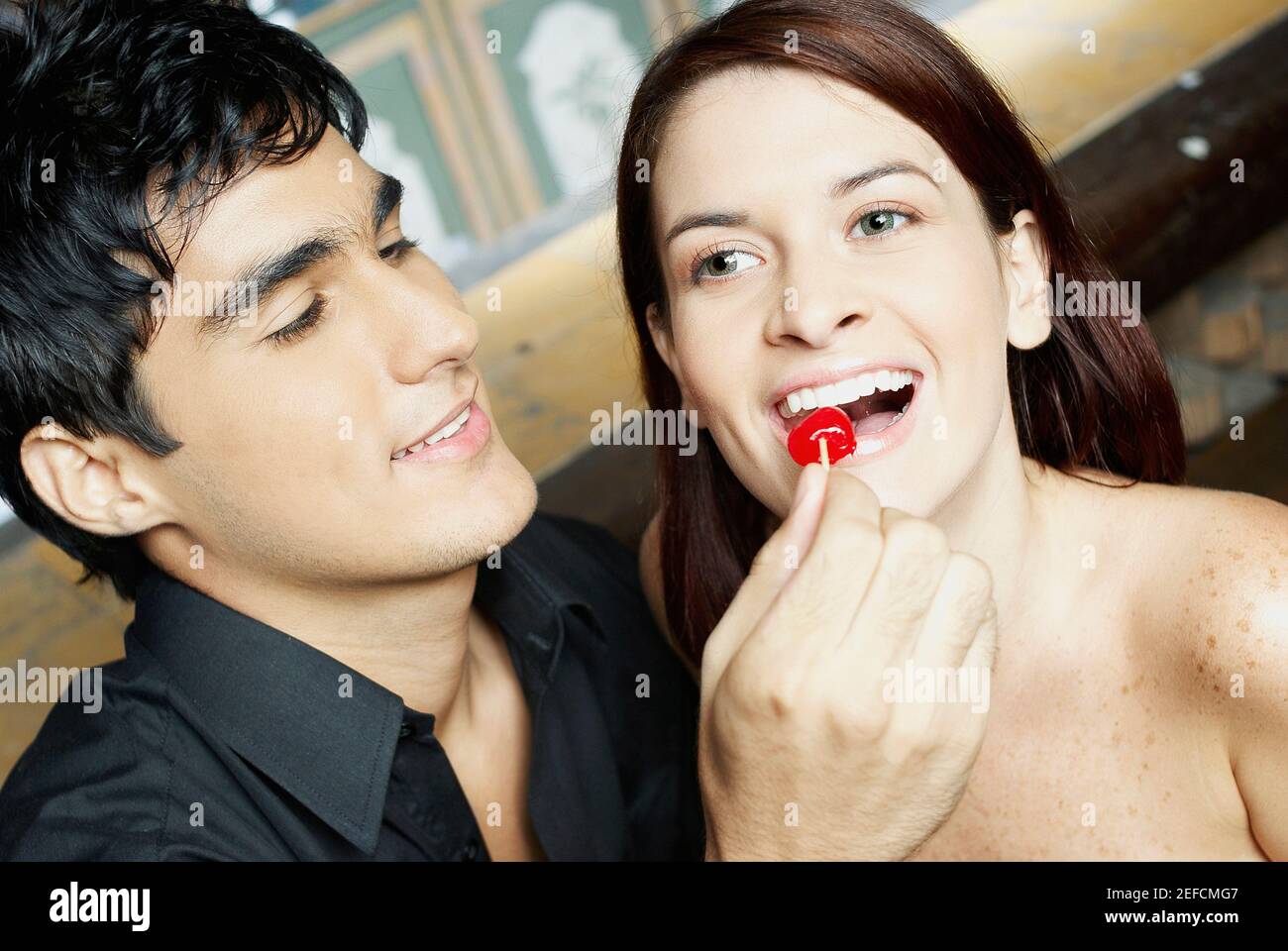 Close up of a young man feeding a cherry to a young woman Stock Photo ...