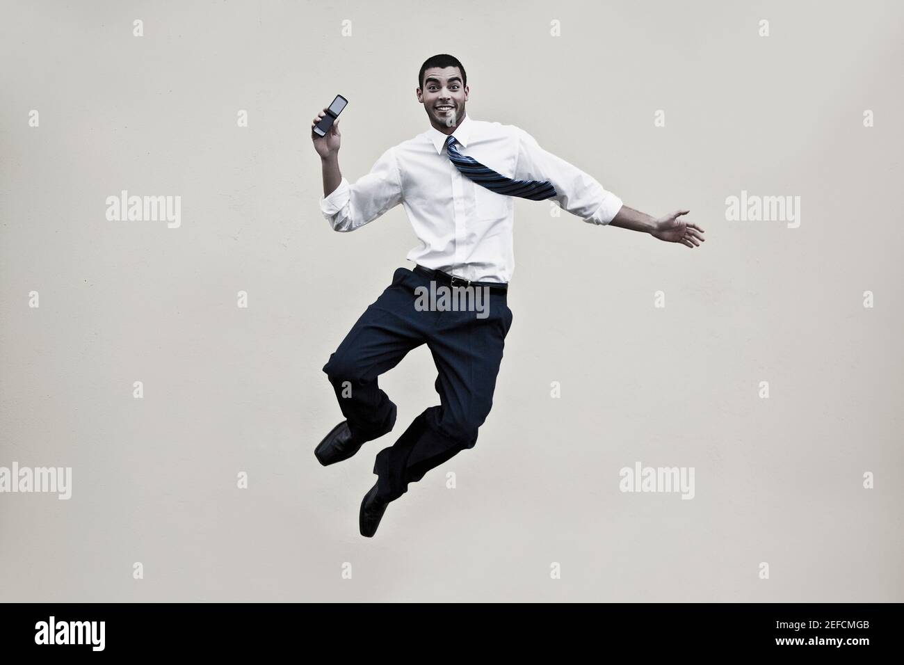 Portrait of a businessman holding a mobile phone and jumping Stock ...