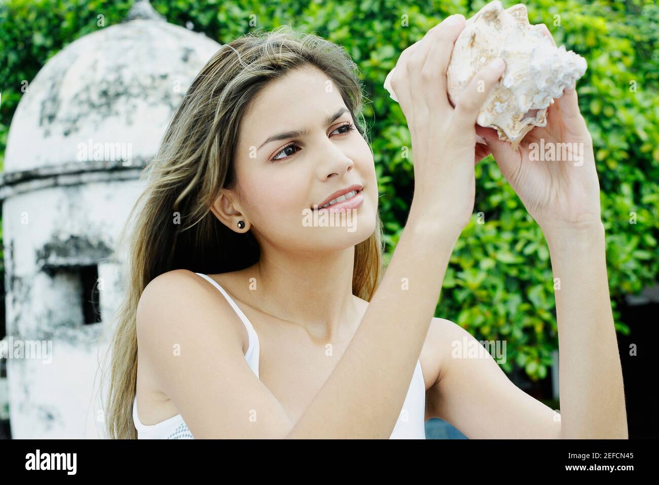 Close up of a young woman holding a conch shell Stock Photo - Alamy