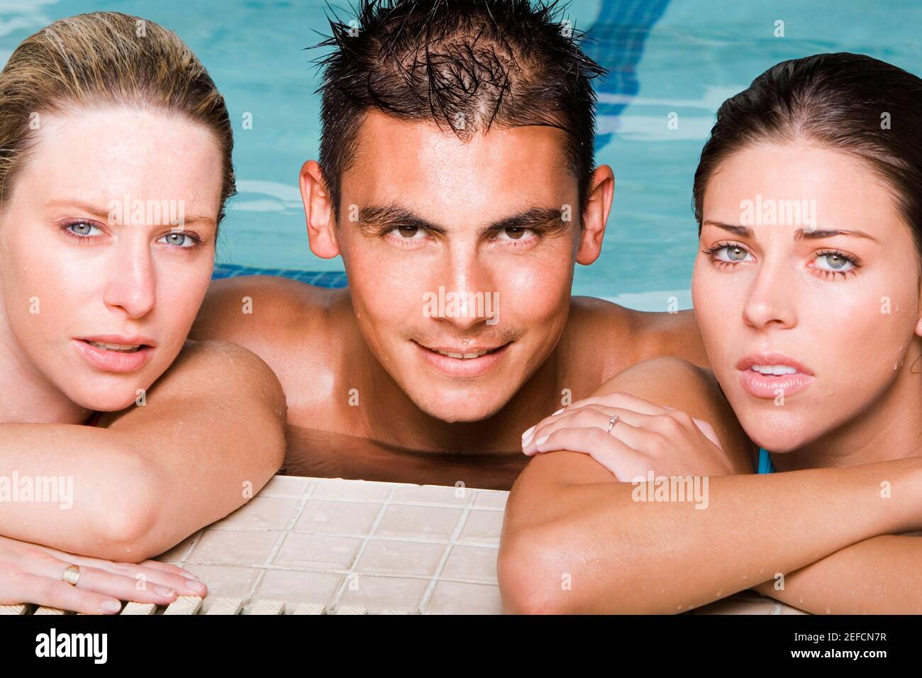 Portrait of a young man and two young women leaning at the edge of a ...