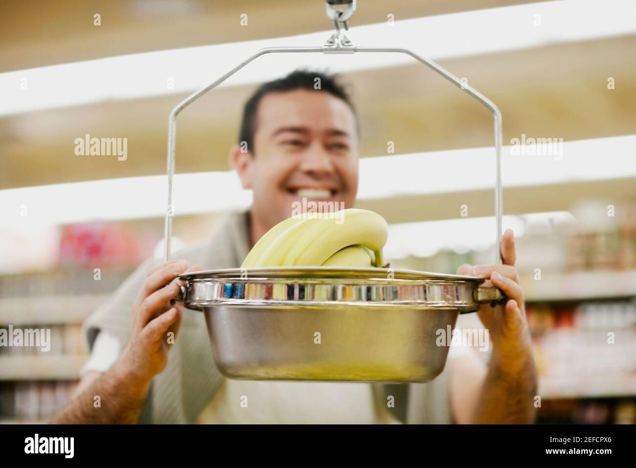 Close up of a mid adult man holding a weighing scale and smiling Stock ...