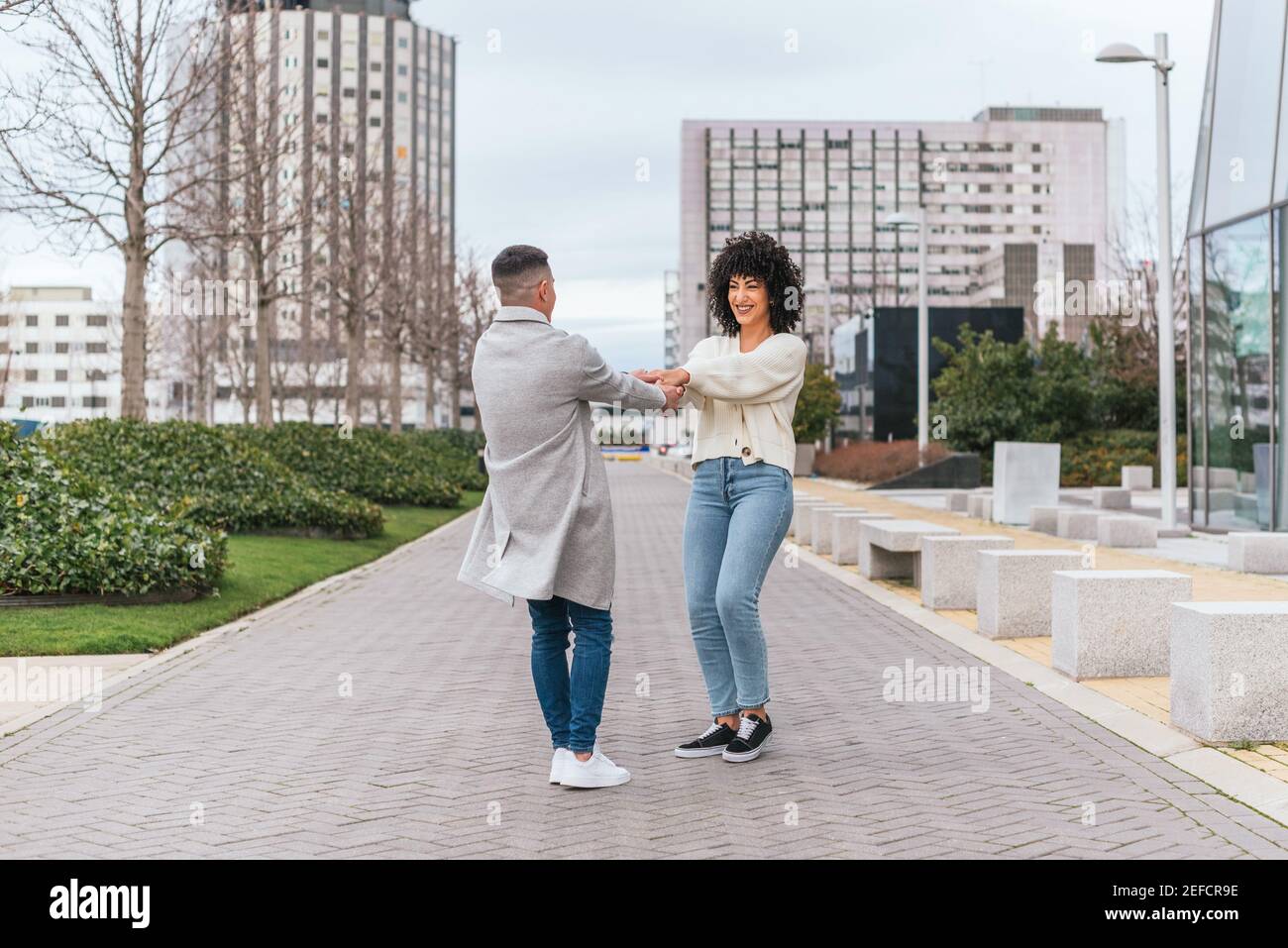 Shallow focus of a young cheerful couple spinning around near modern ...