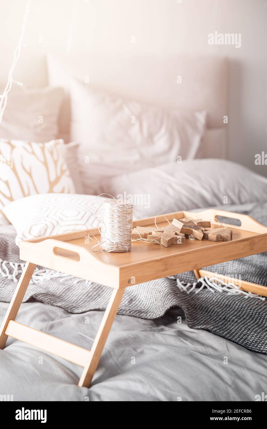 Wooden small breakfast table stands on bed in bedroom, gray sheets, sun ...