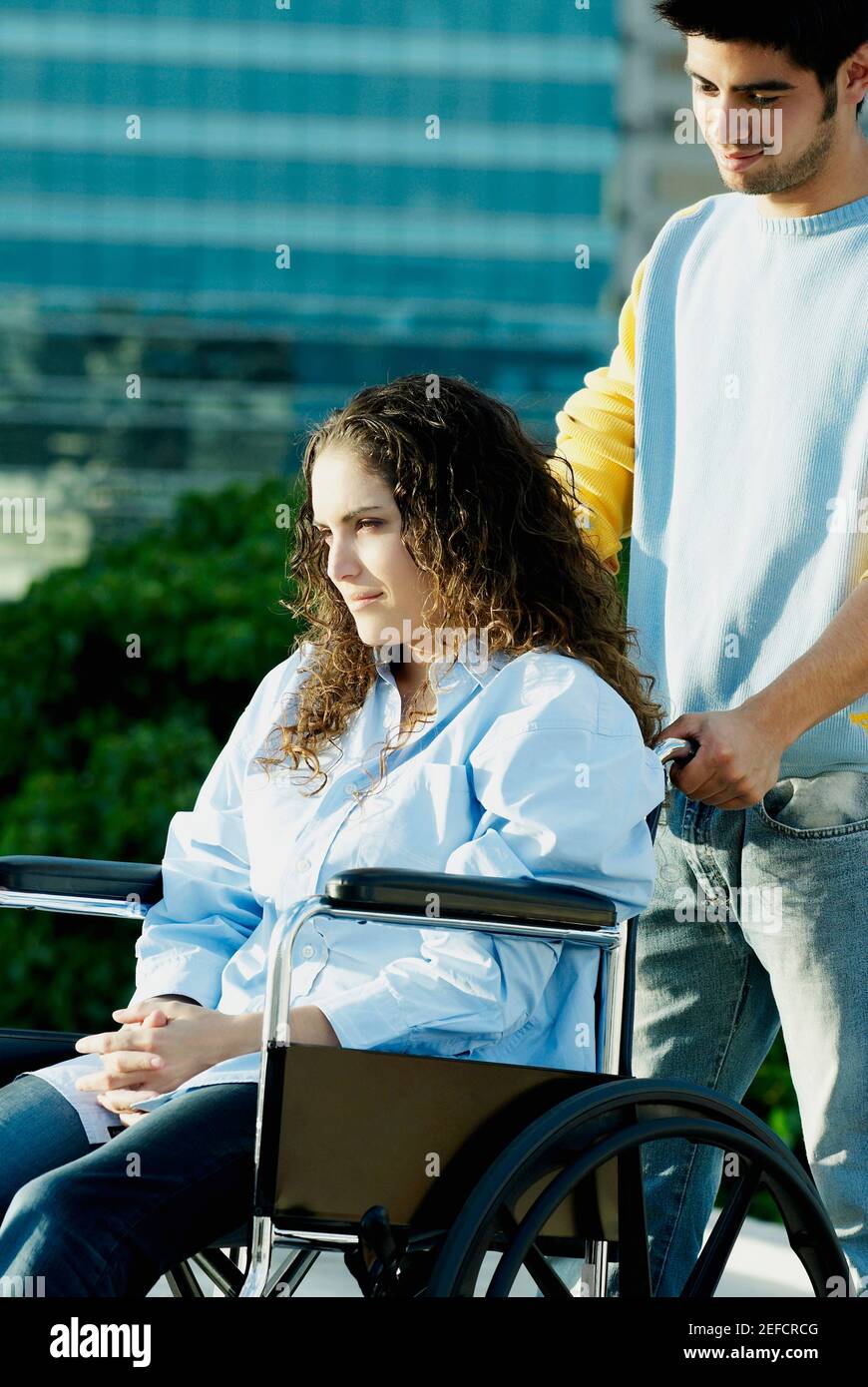 Young man pushing a wheelchair with a young woman Stock Photo - Alamy