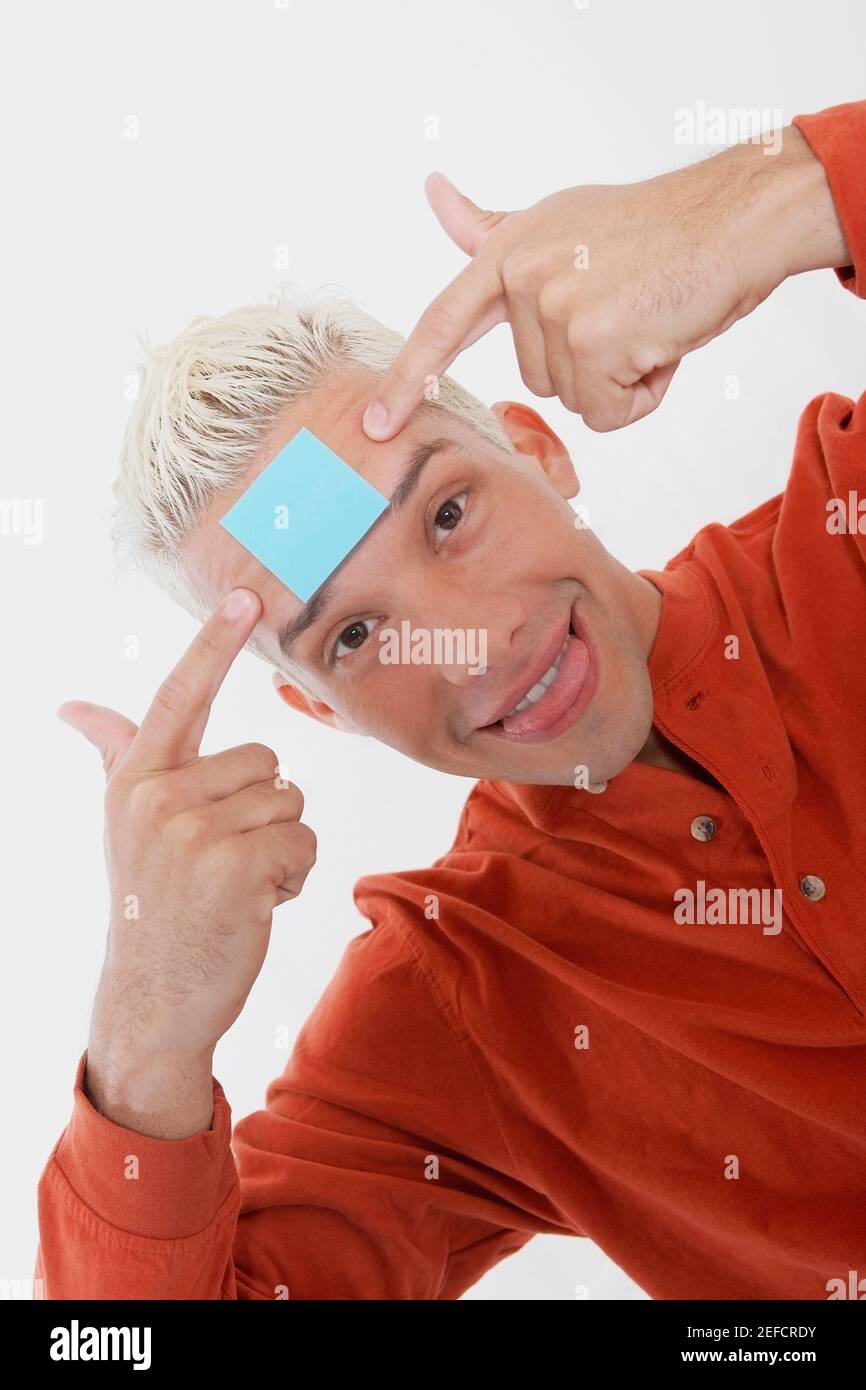 Portrait of a young man smiling with an adhesive note on his forehead ...