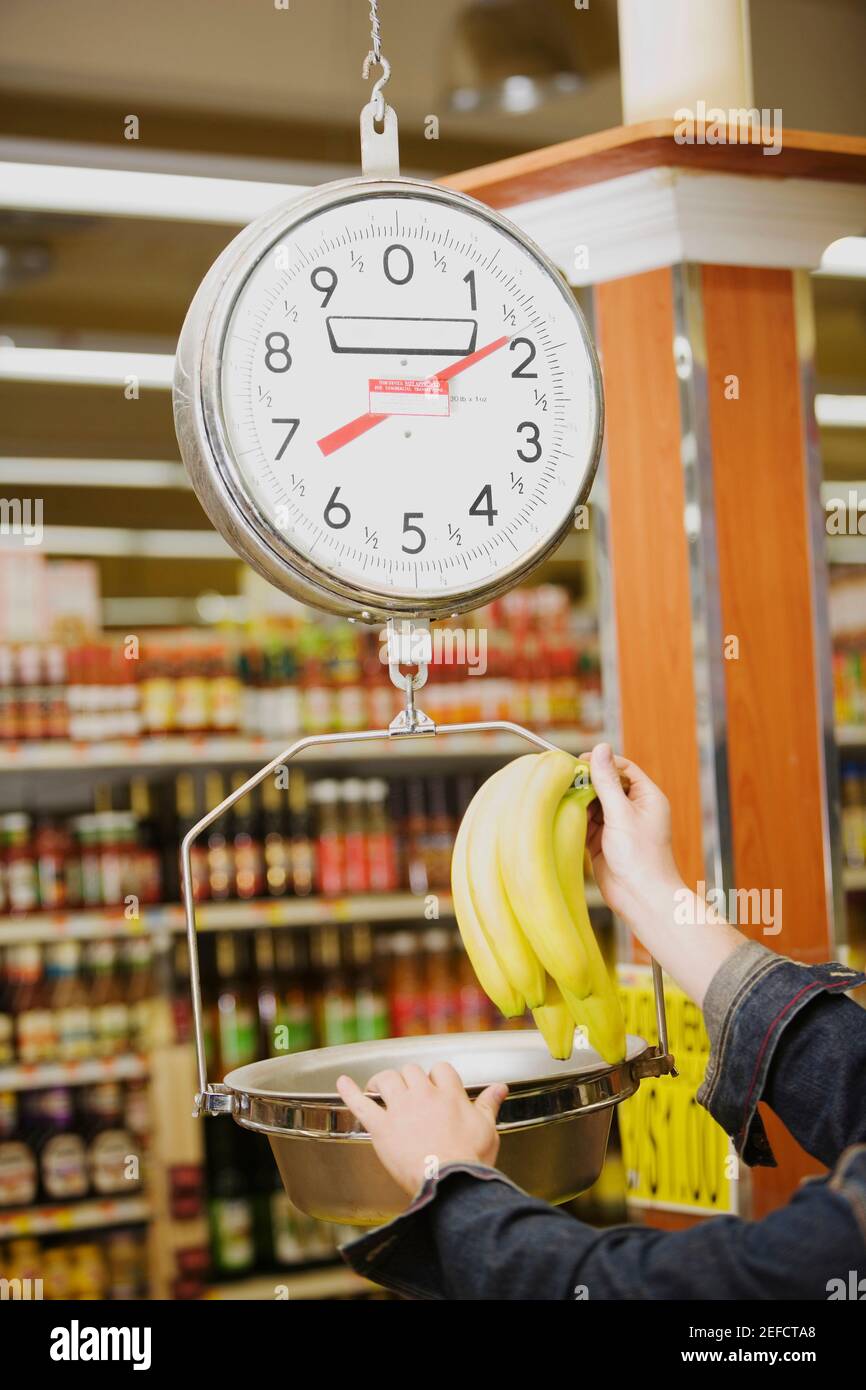 ManŽs hand weighing a bunch of bananas on a weighing scale in a ...