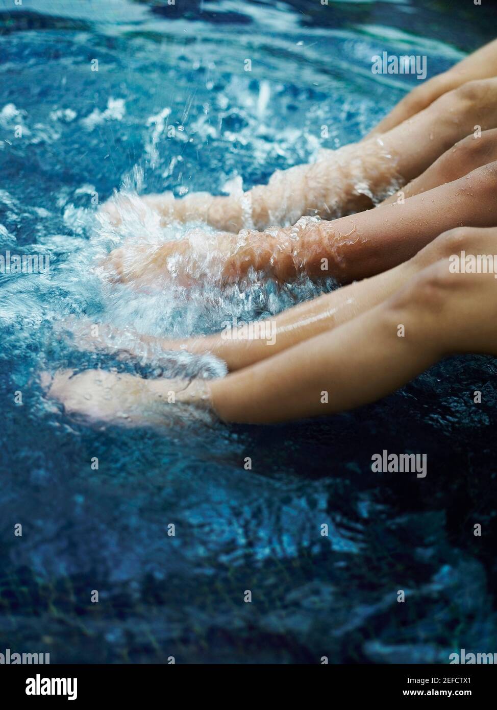 Low section view of three people flapping their legs in water Stock ...